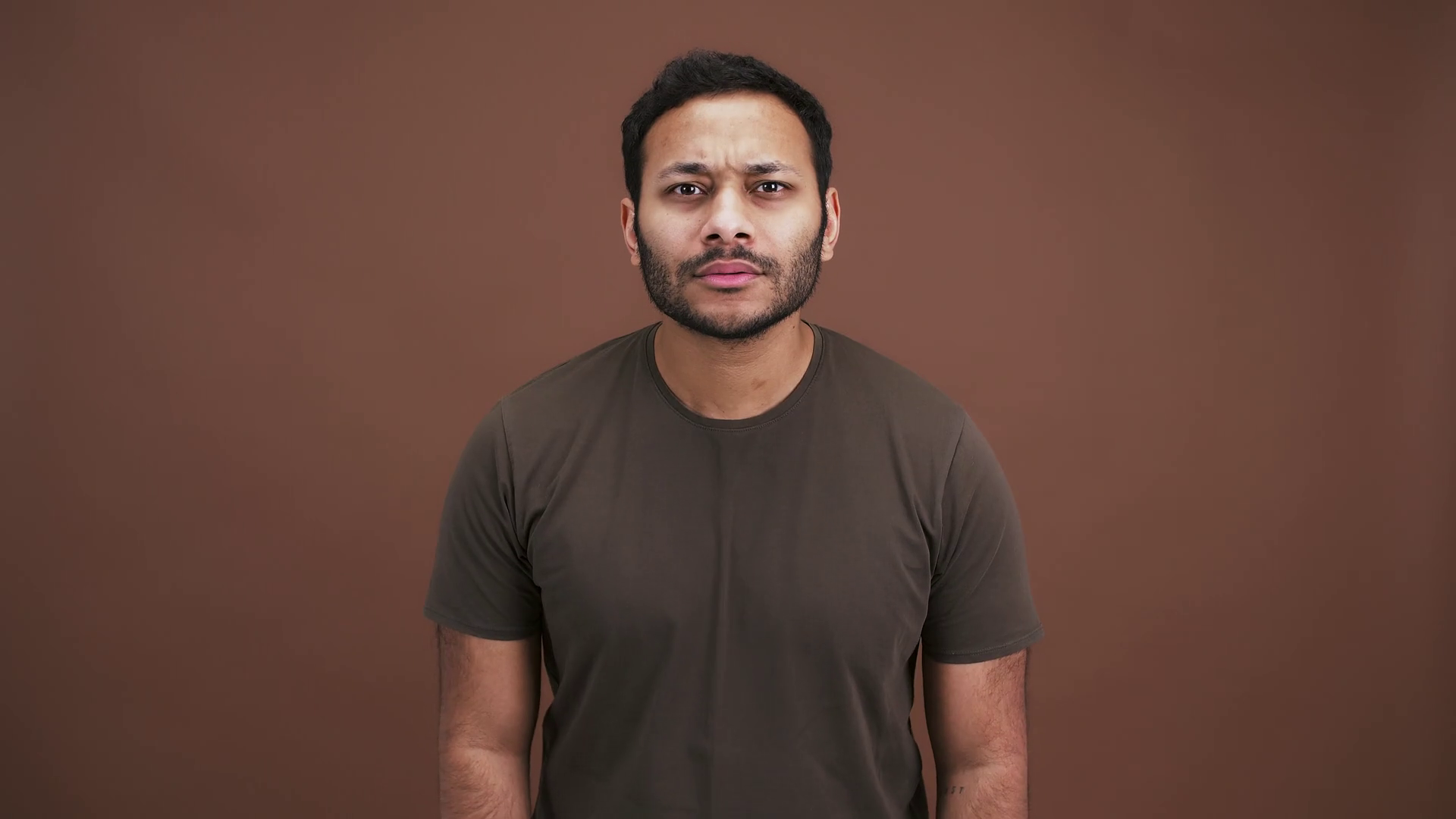 Studio shot of indian man looking at camera with expectation, seeing ...