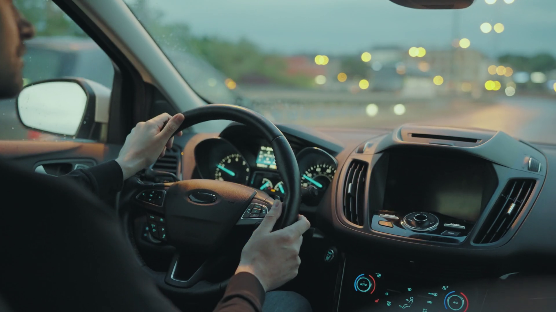 Man driving car through the streets of evening city. View from the back ...