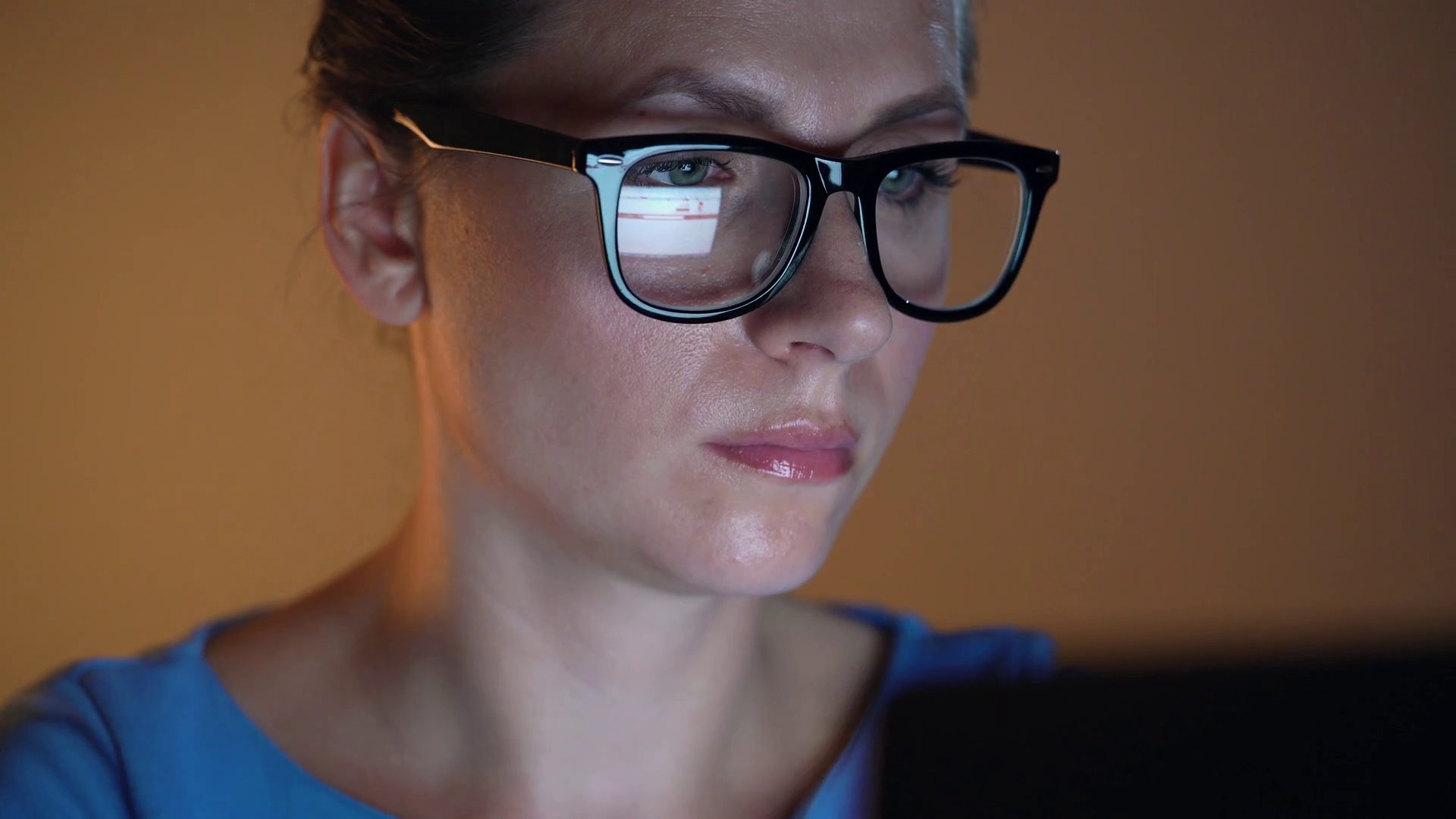 Woman in glasses looking on the monitor and surfing Internet at night ...
