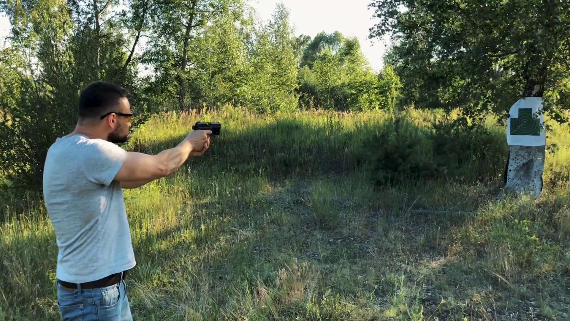 Young man is shooting from a gun at the target, close up. Slow motion ...