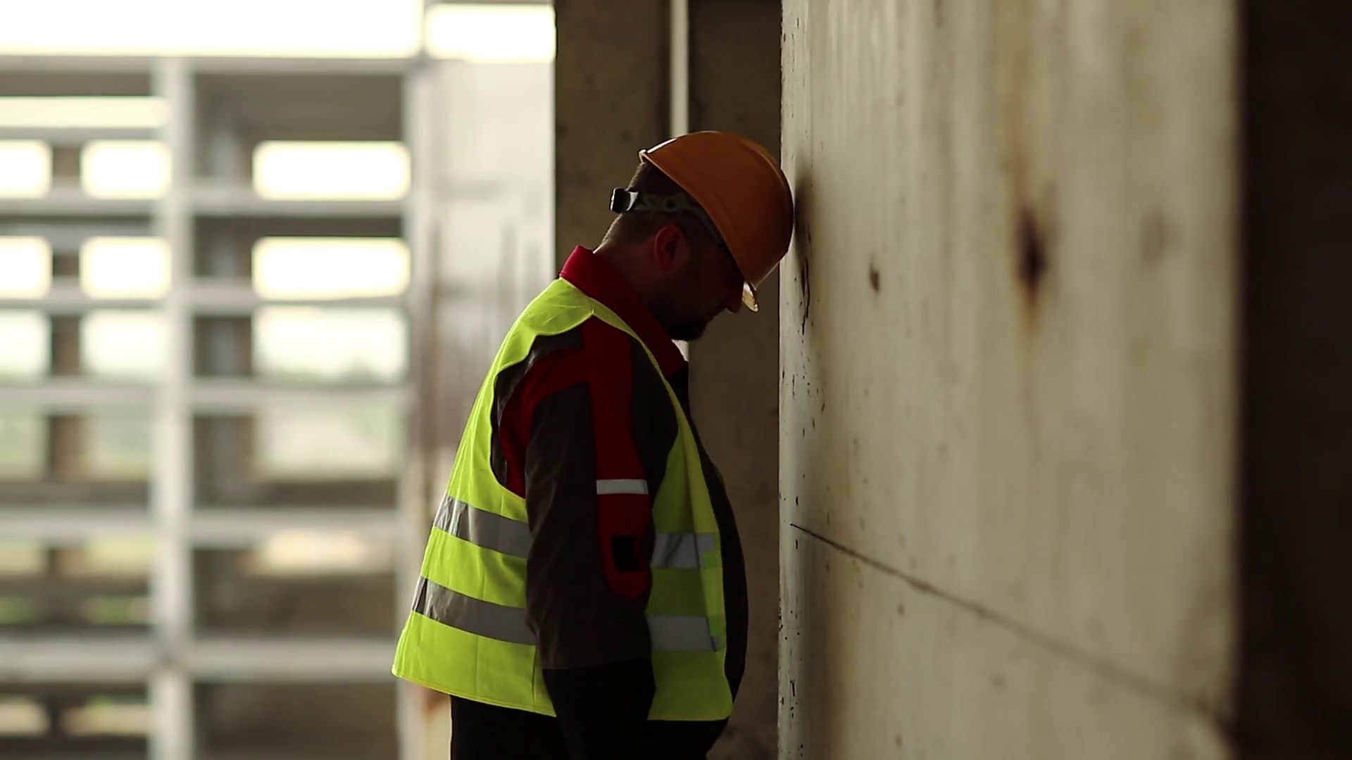 Builder knocks his head against the wall. Stressed worker in hard hat ...