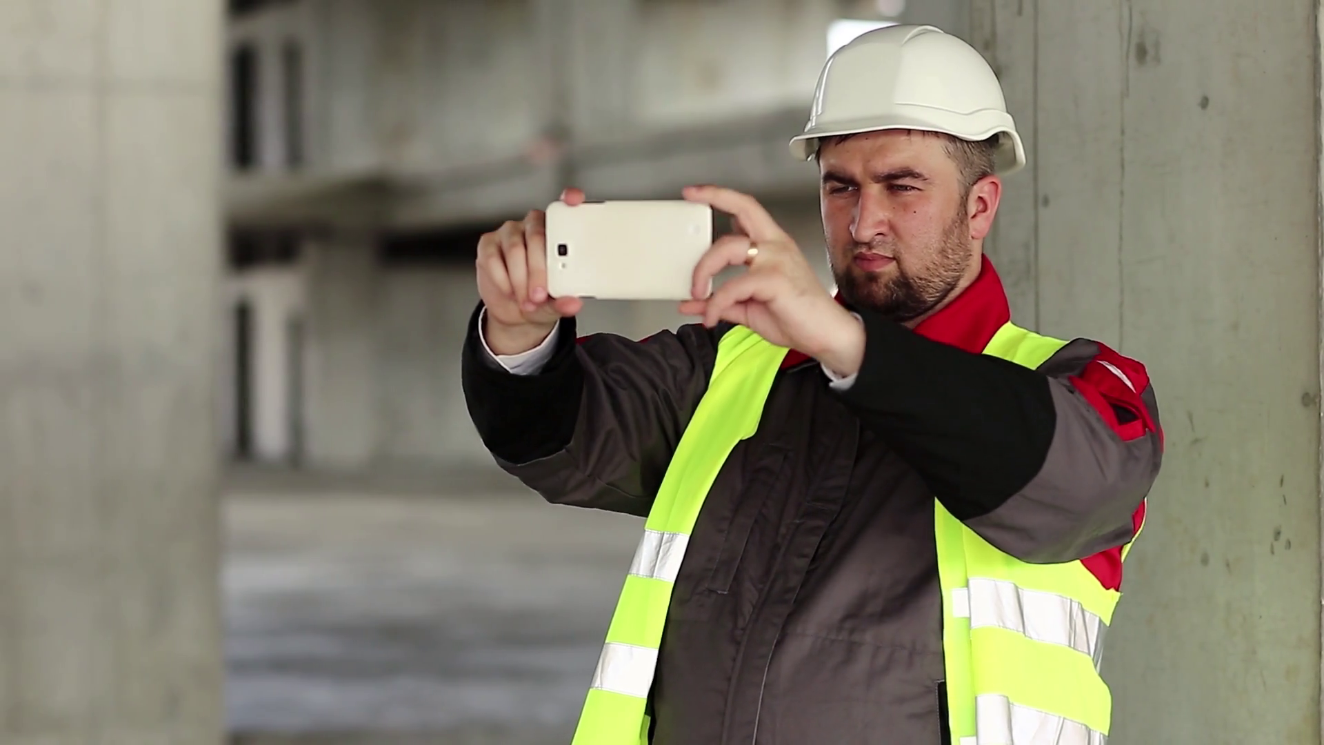 Builder records videos on smartphone. Worker at construction site makes ...