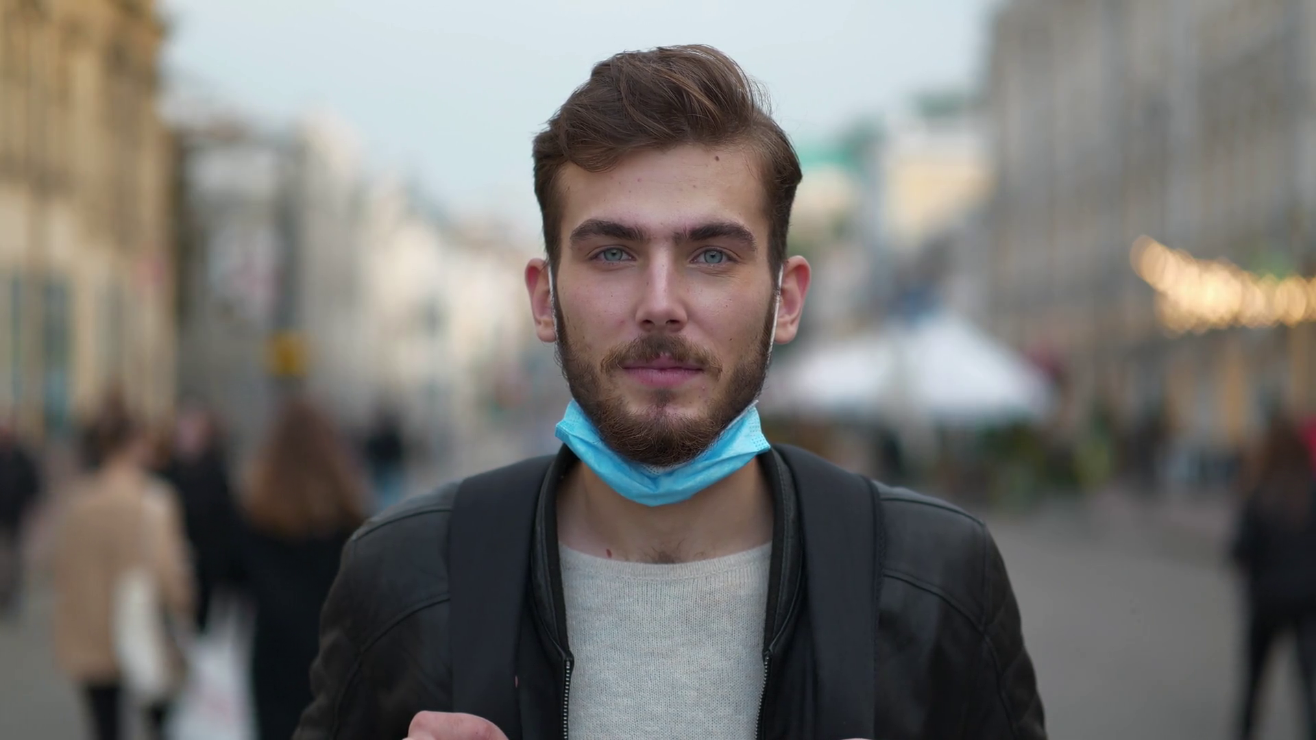 Guy in medical protective mask on the chin stands on the street and ...
