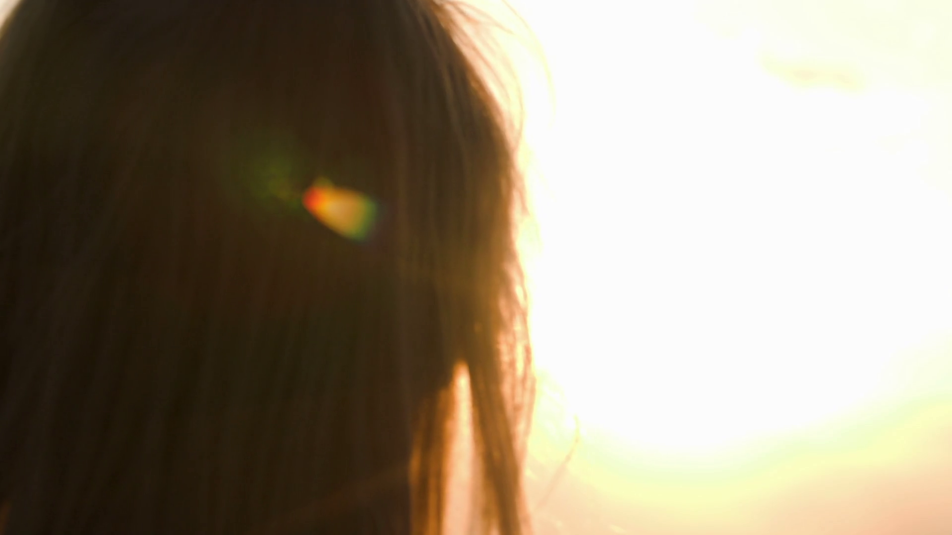 Back close-up shot of woman looking into distance hiding from the sun ...