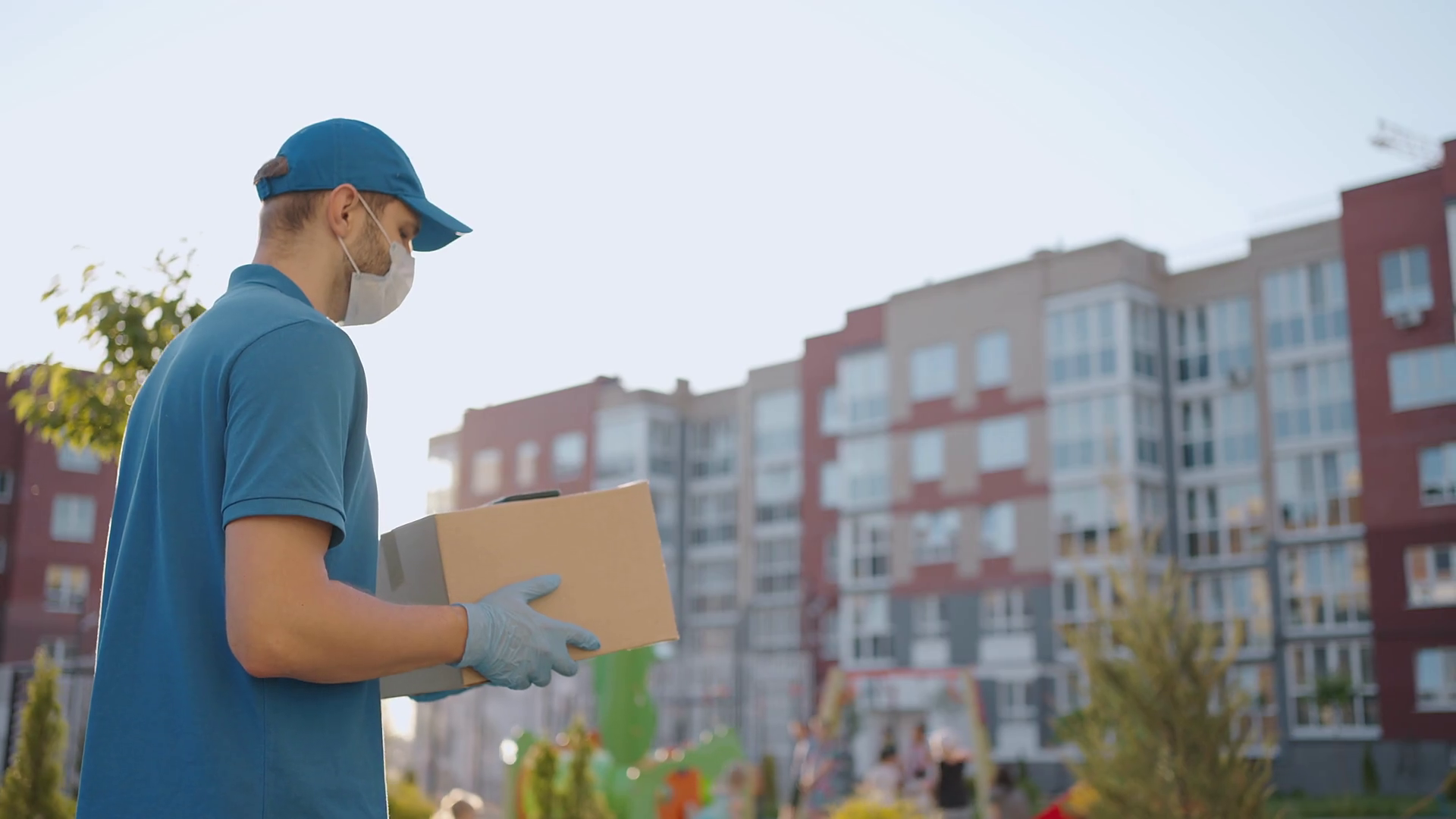 An young mailman courier with a protective mask and gloves is ...