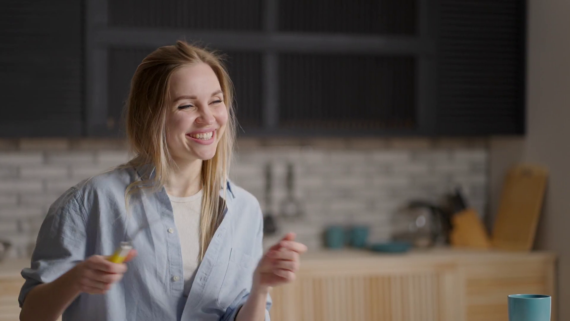Happy young woman dancing singing while cooking in modern kitchen ...