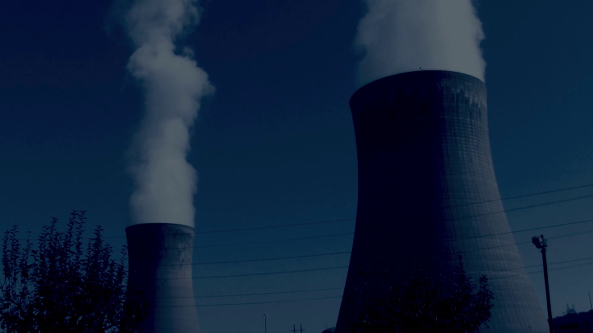 Two nuclear power plant cooling towers vent smoke into the night sky ...