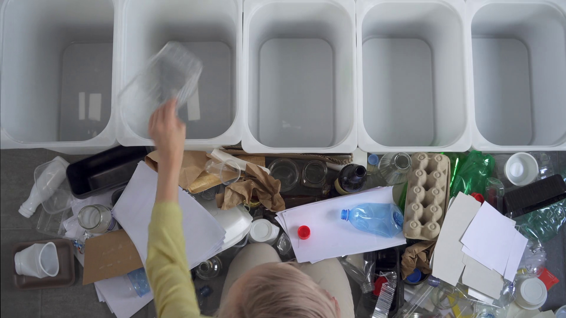 Young woman is sorting garbage into containers sitting on floor in home ...