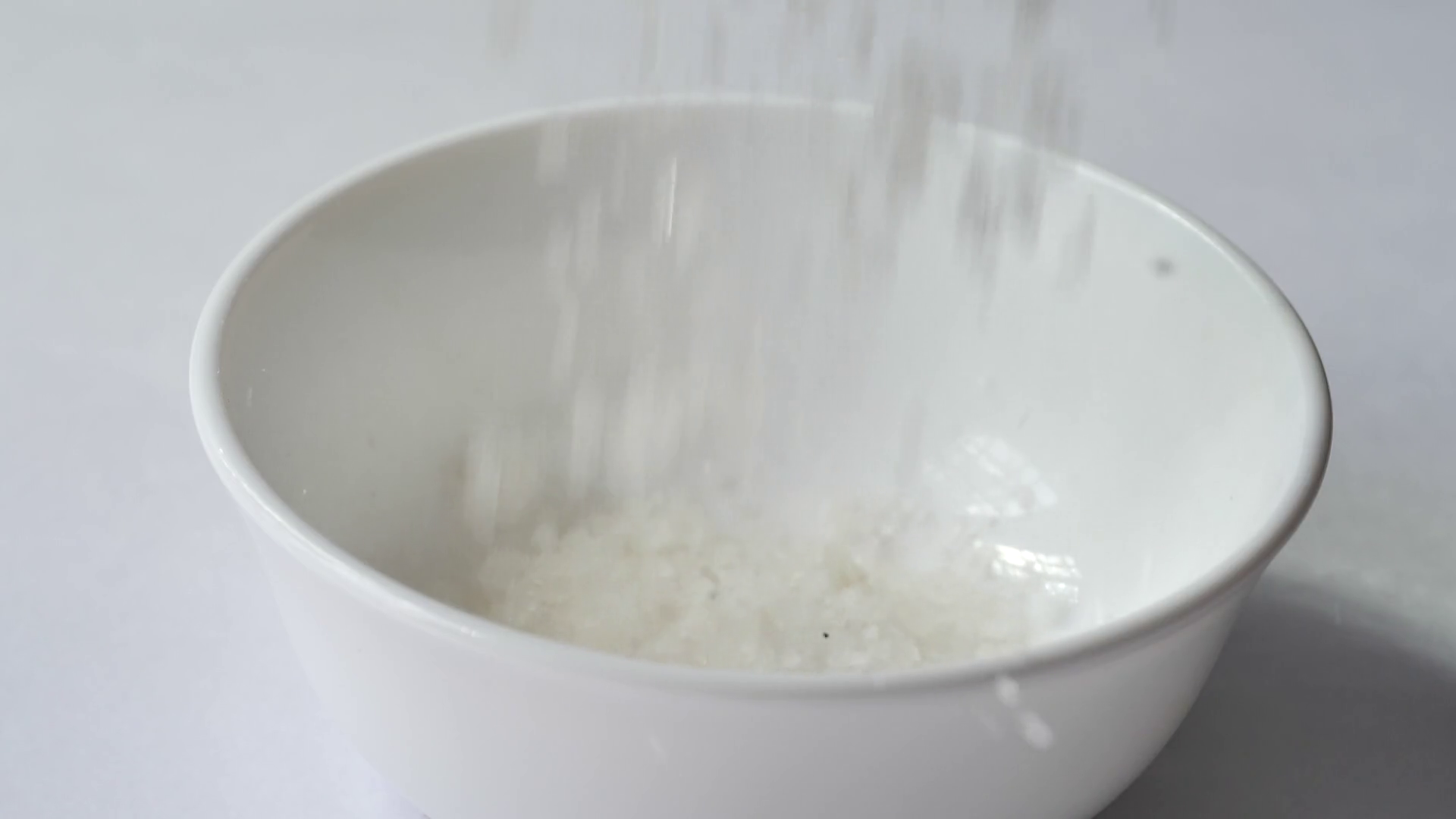 Crystal Salt Falling Into A Black Bowl Stock Video Footage - Storyblocks
