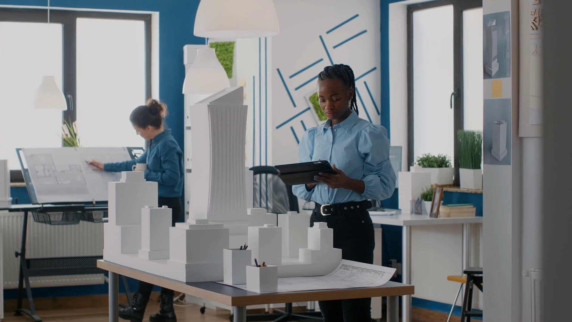 Architect using digital tablet to design layout of building model and ...