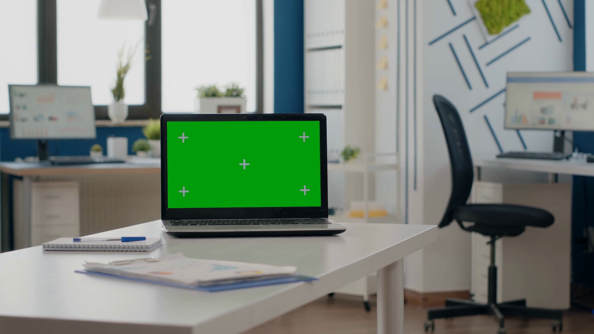 Close up of empty desk with green screen on laptop in startup office ...
