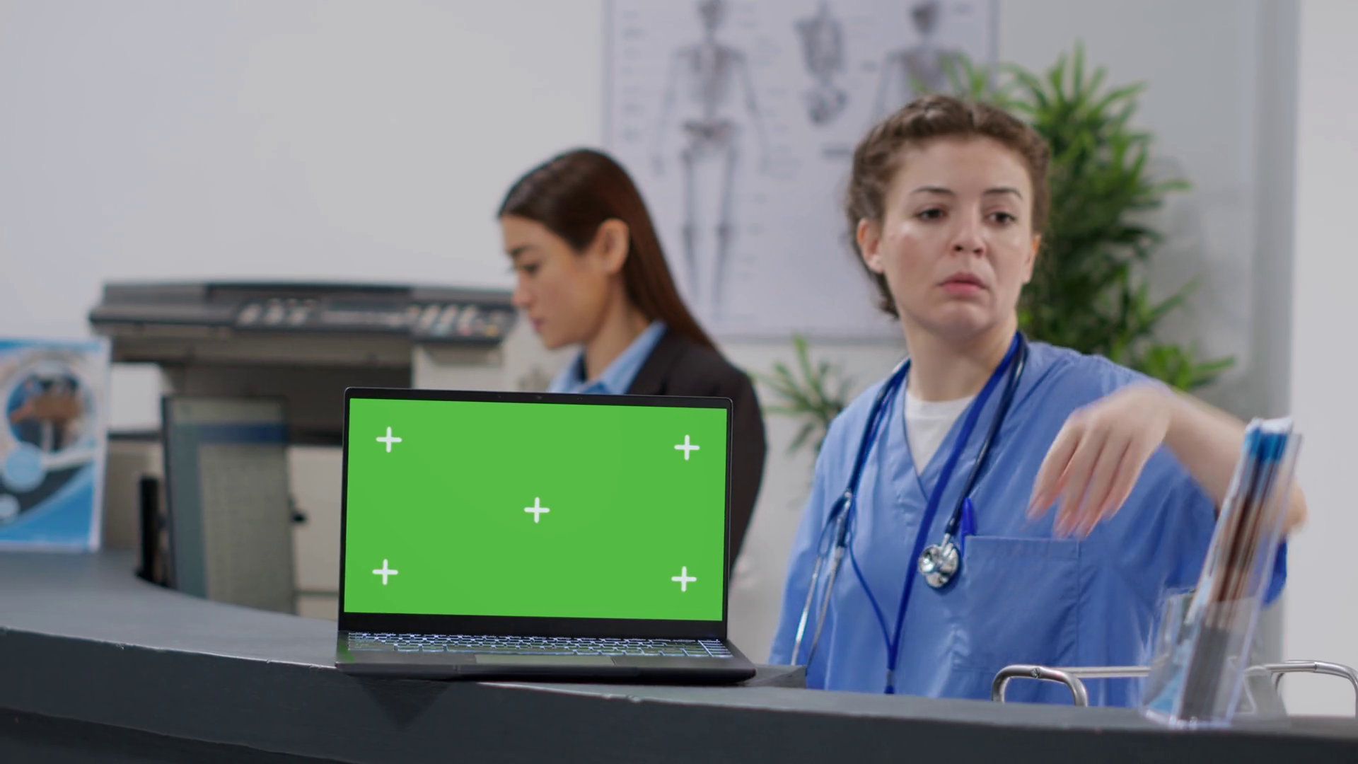Nurse and receptionist working with greenscreen on laptop at facility ...