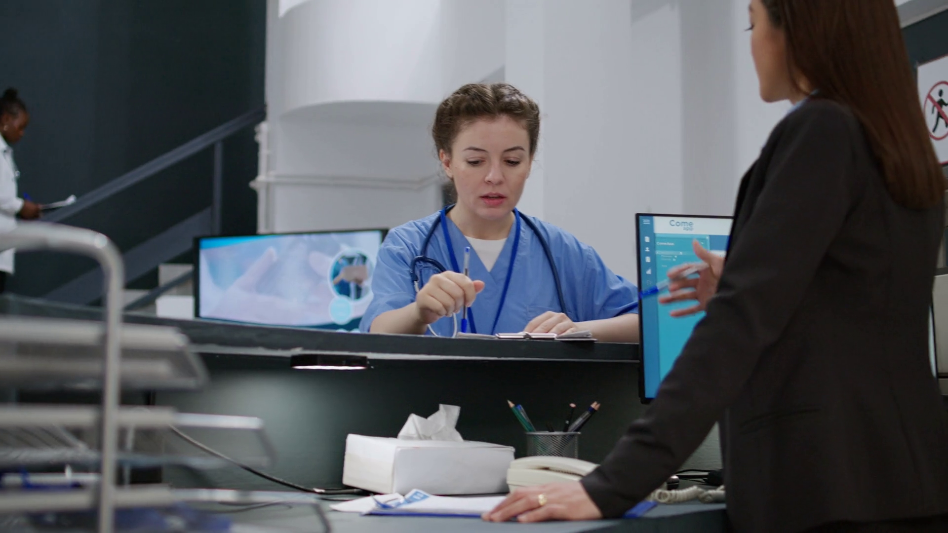 Portrait of medical assistant talking to receptionist at hospital ...