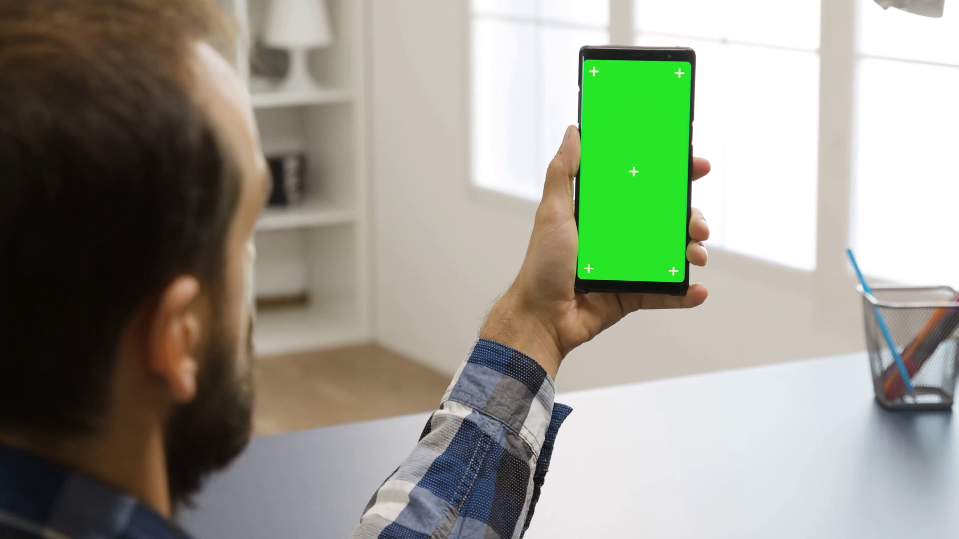 Man looking at phone with green screen in modern, bright and well lit ...