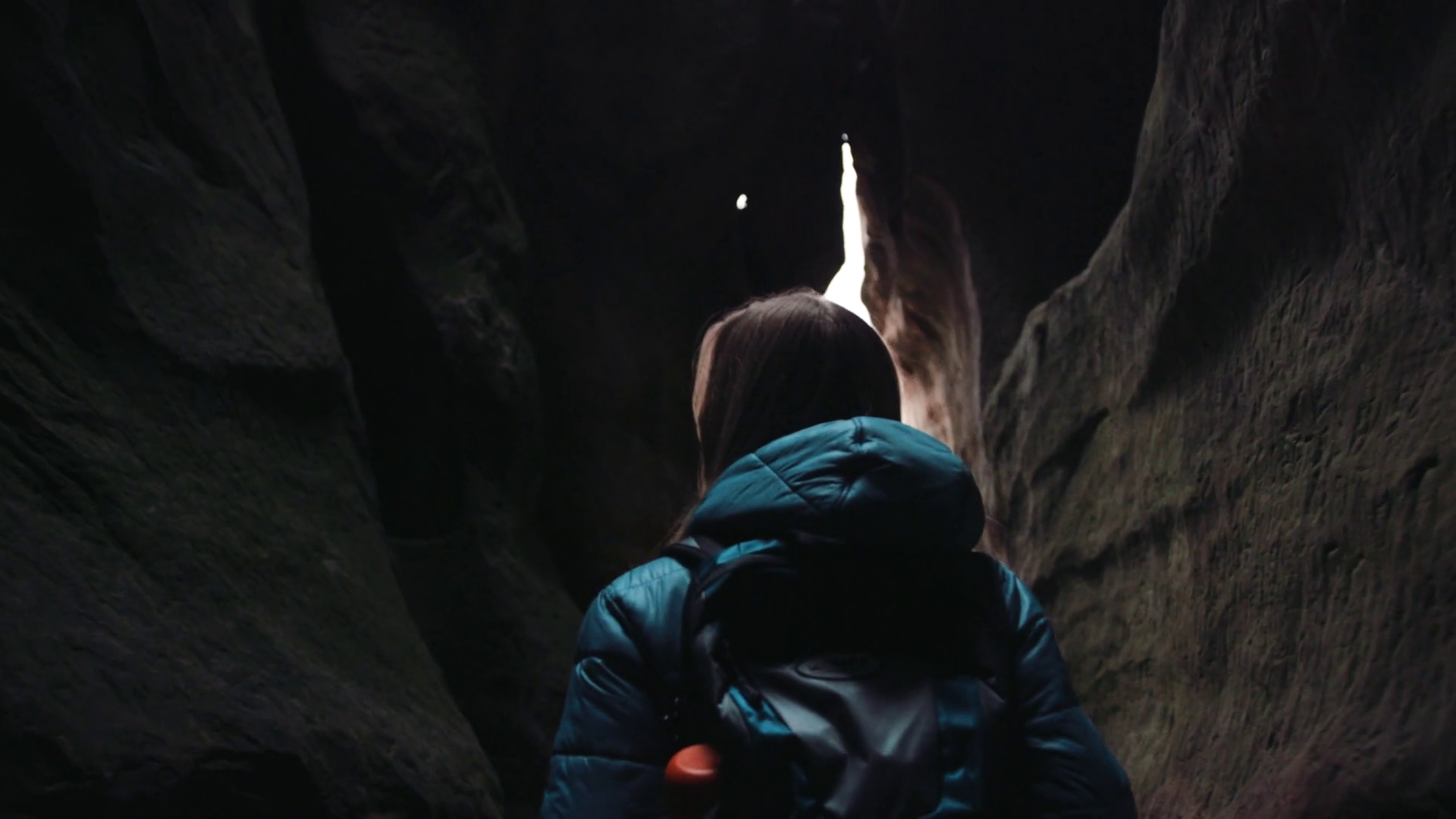 Scared young blonde woman with a backpack walking lost in the dark cave ...