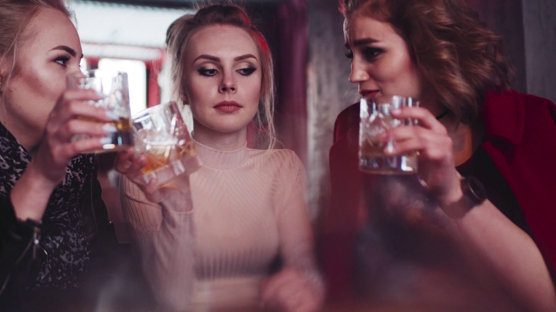 Three pretty girls having a conversation, laughing and drinking alcohol ...