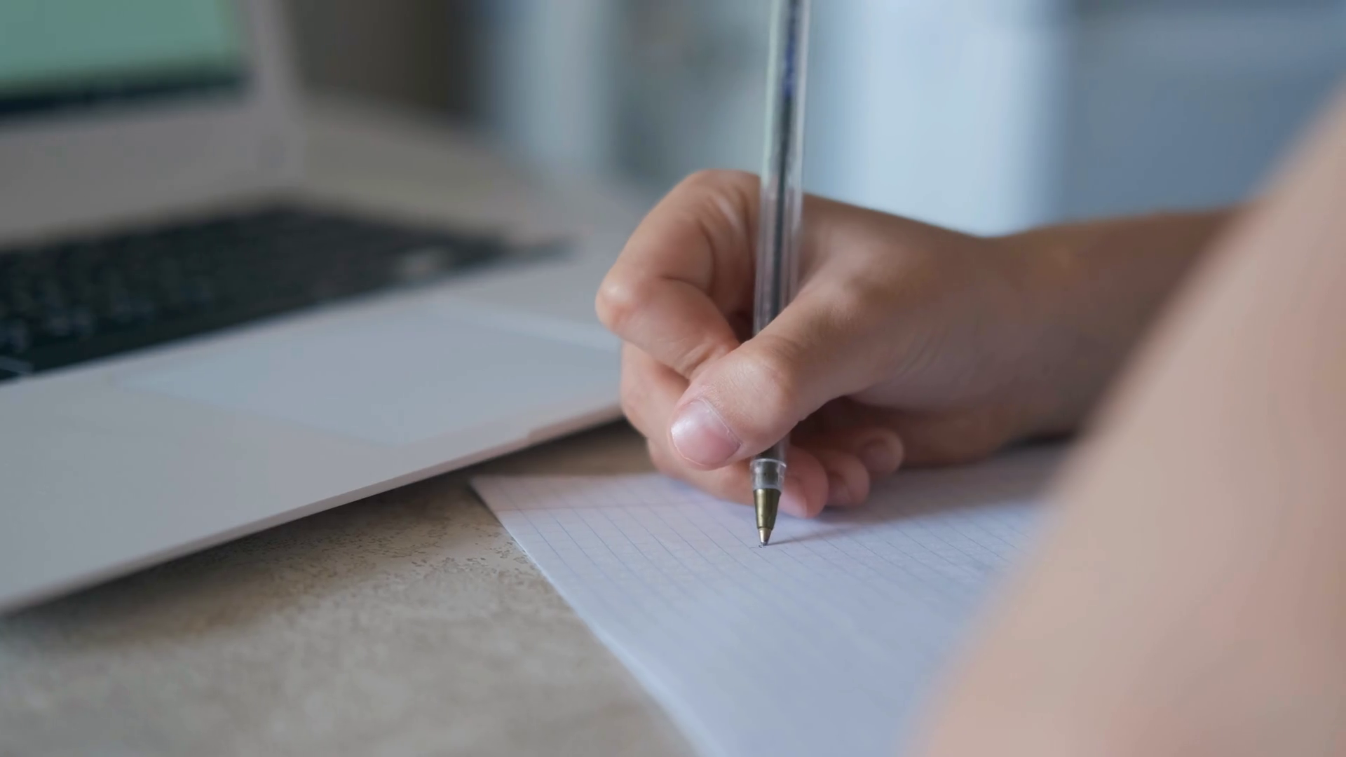 Close-up of hands with a fountain pen, laptop. A child writes in a ...