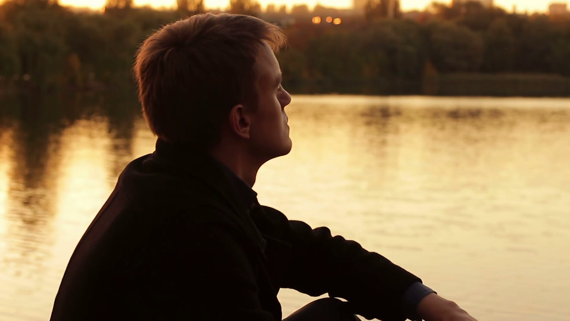 Sad guy by the river at sunset Stock Video Footage - Storyblocks