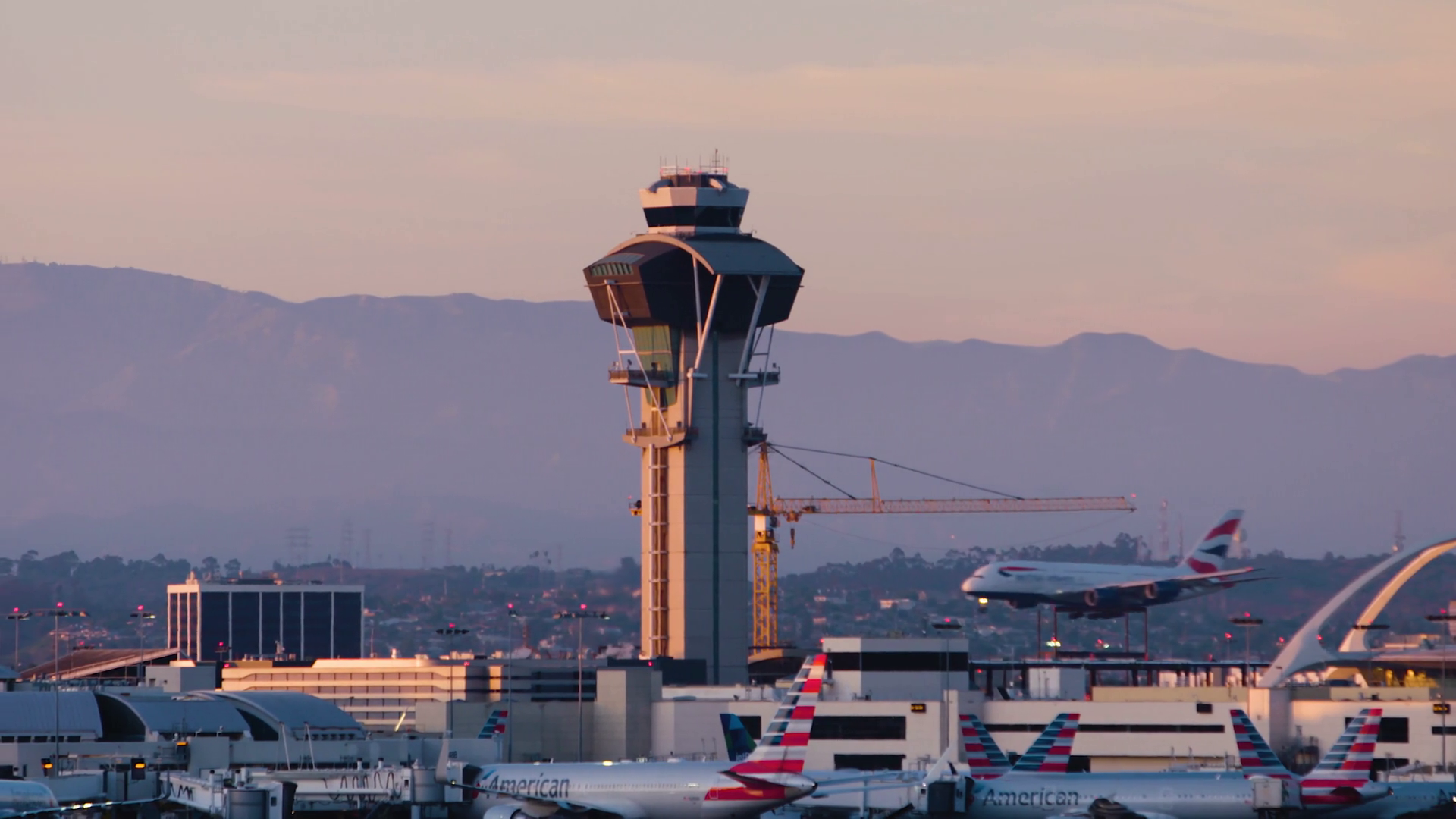 Huge jet airliner passes behind atc tower at LAX airport at sunset ...