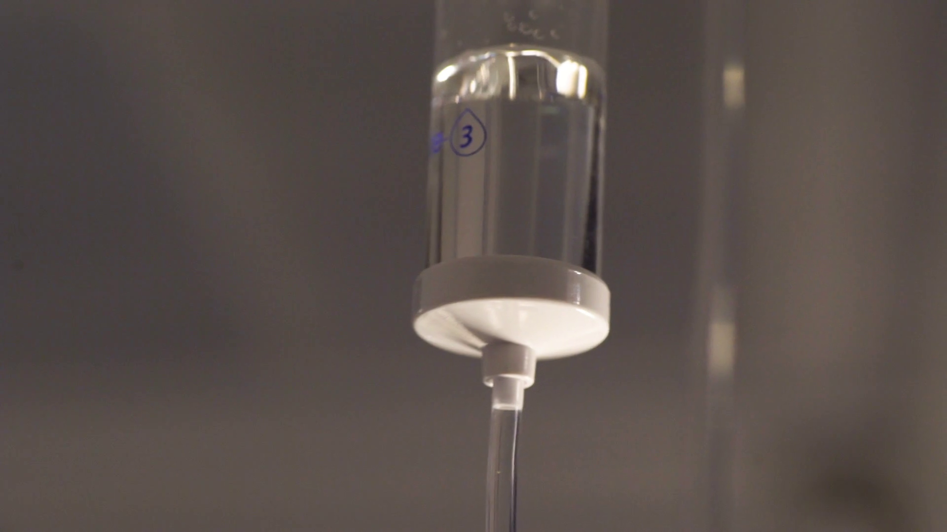 Macro closeup, plastic tubing and an IV or drip container in a medical ...