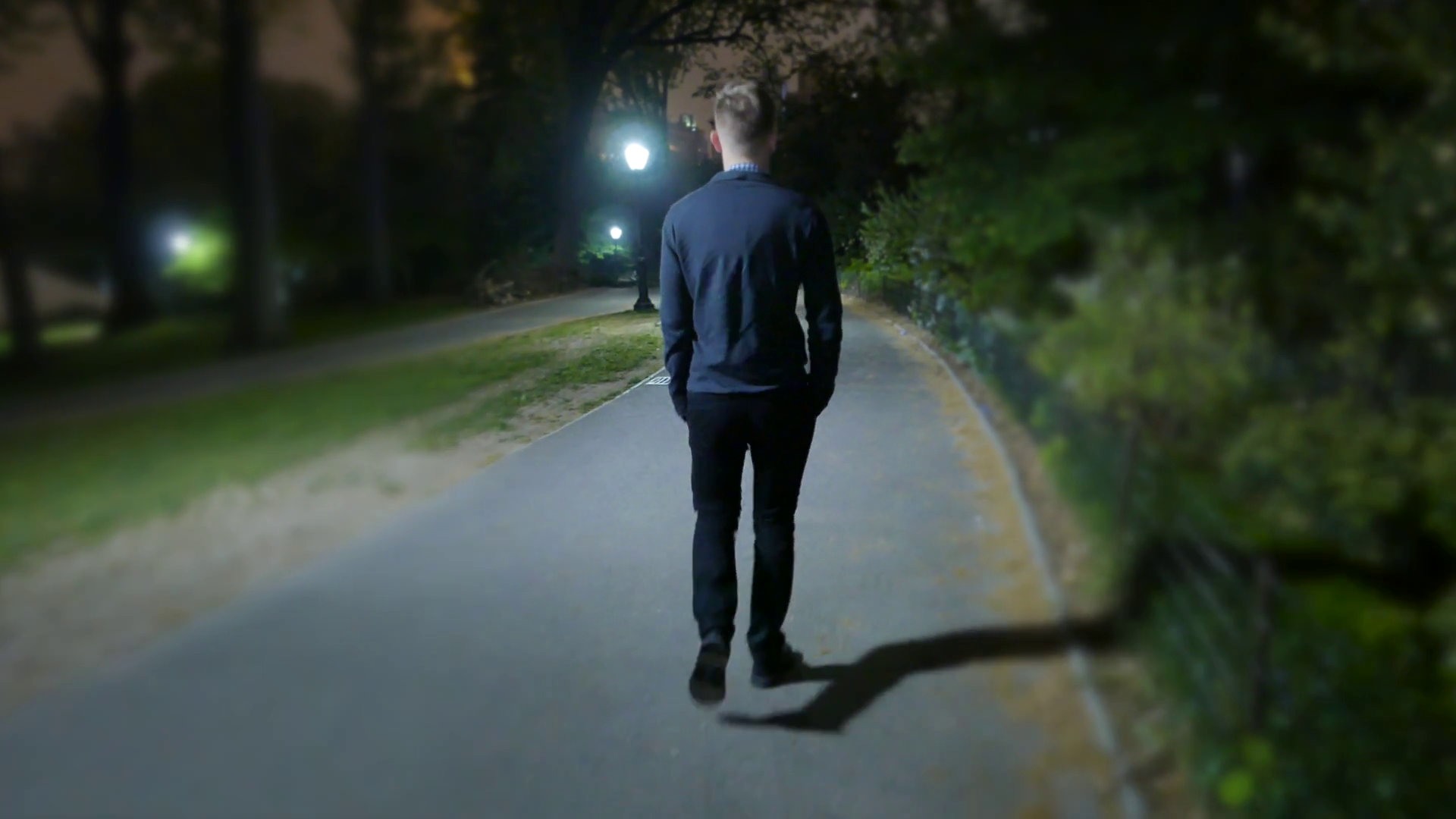 one man walking alone trough city park at night. spooky scary ...