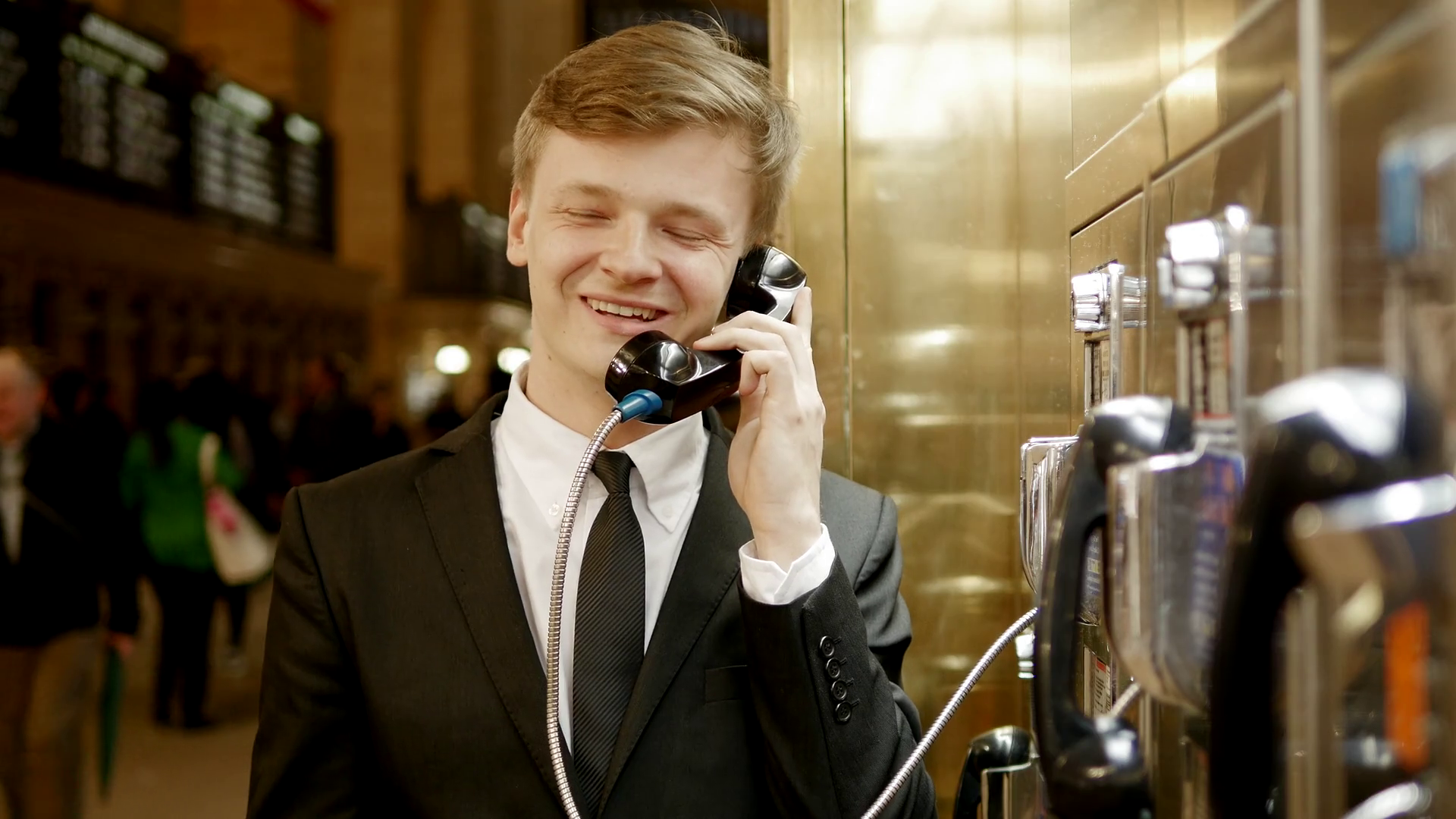 young businessman talking in the phone booth telling success story ...