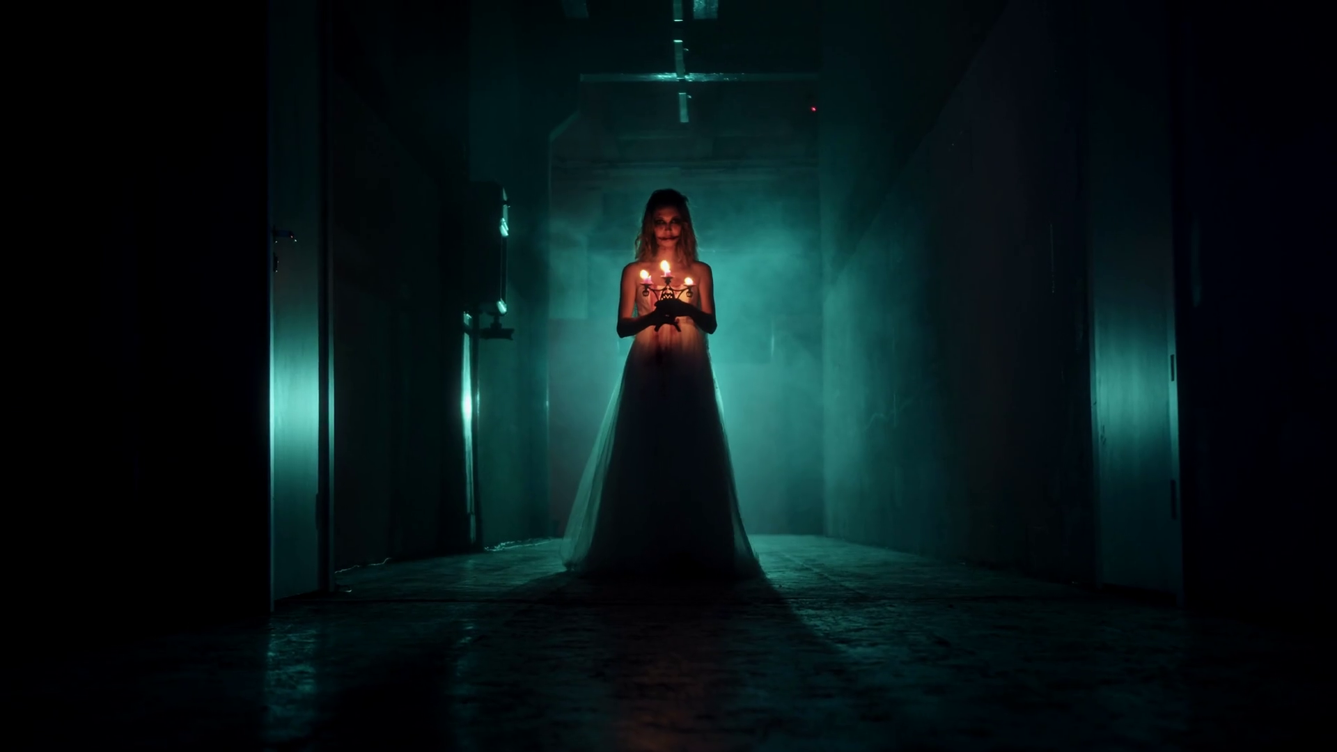 Zombie woman walking with burning candles in dark corridor. Creepy dead ...