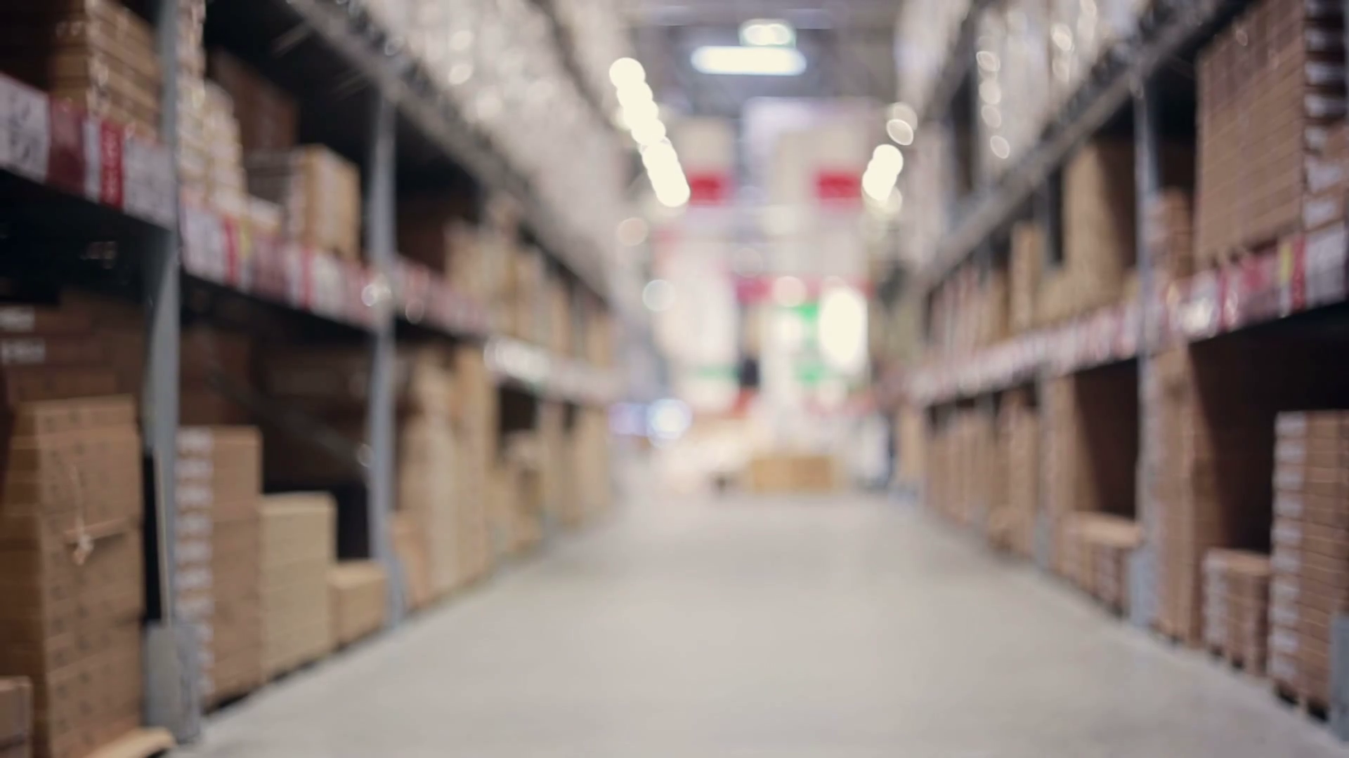 A man is pushing a trolley full of boxes on it between palettes with ...