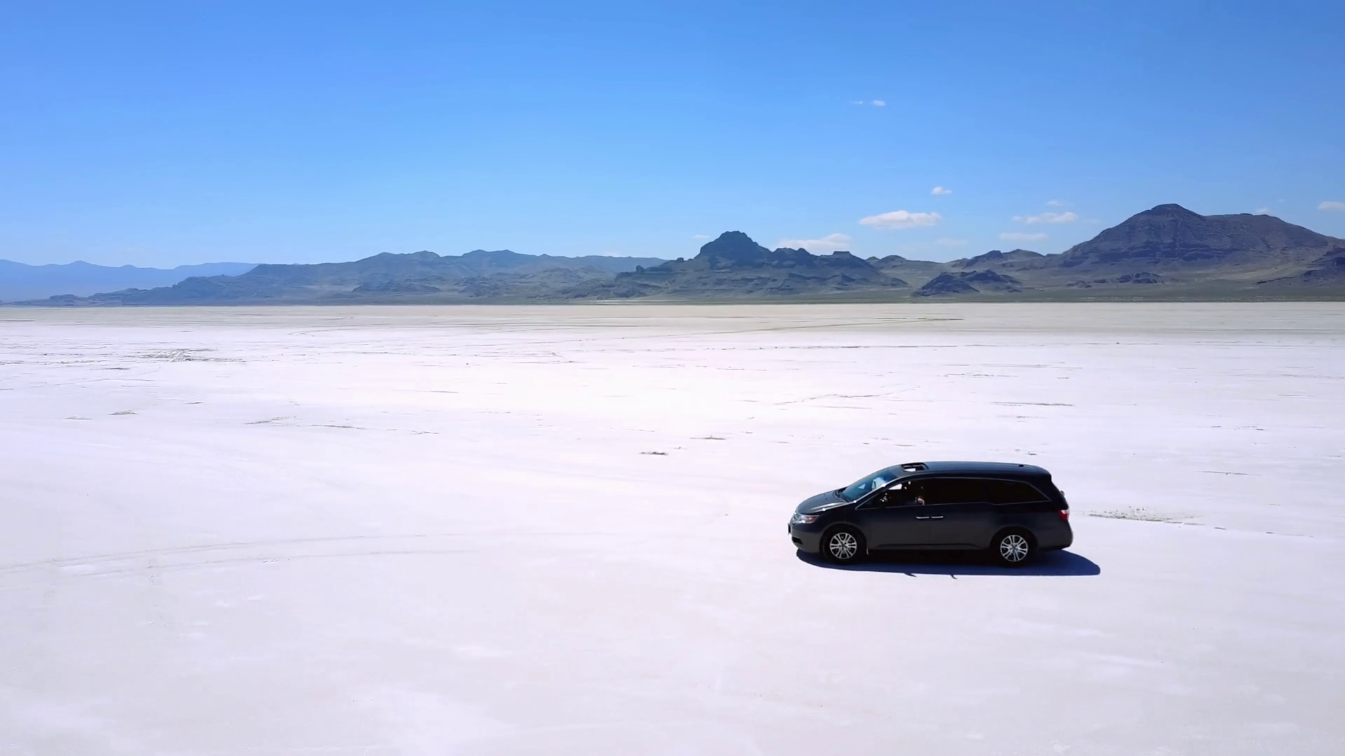 Cinematic aerial drone shot of silver minivan car driving in the middle ...