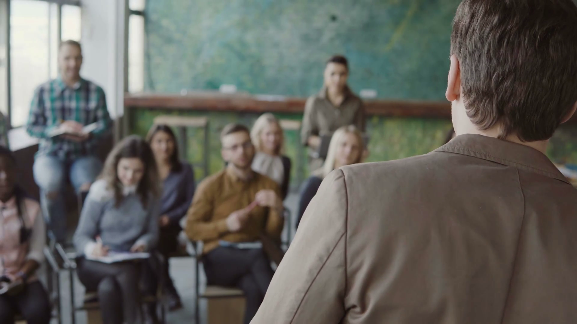 Young businessman standing in front of group of young people and ...