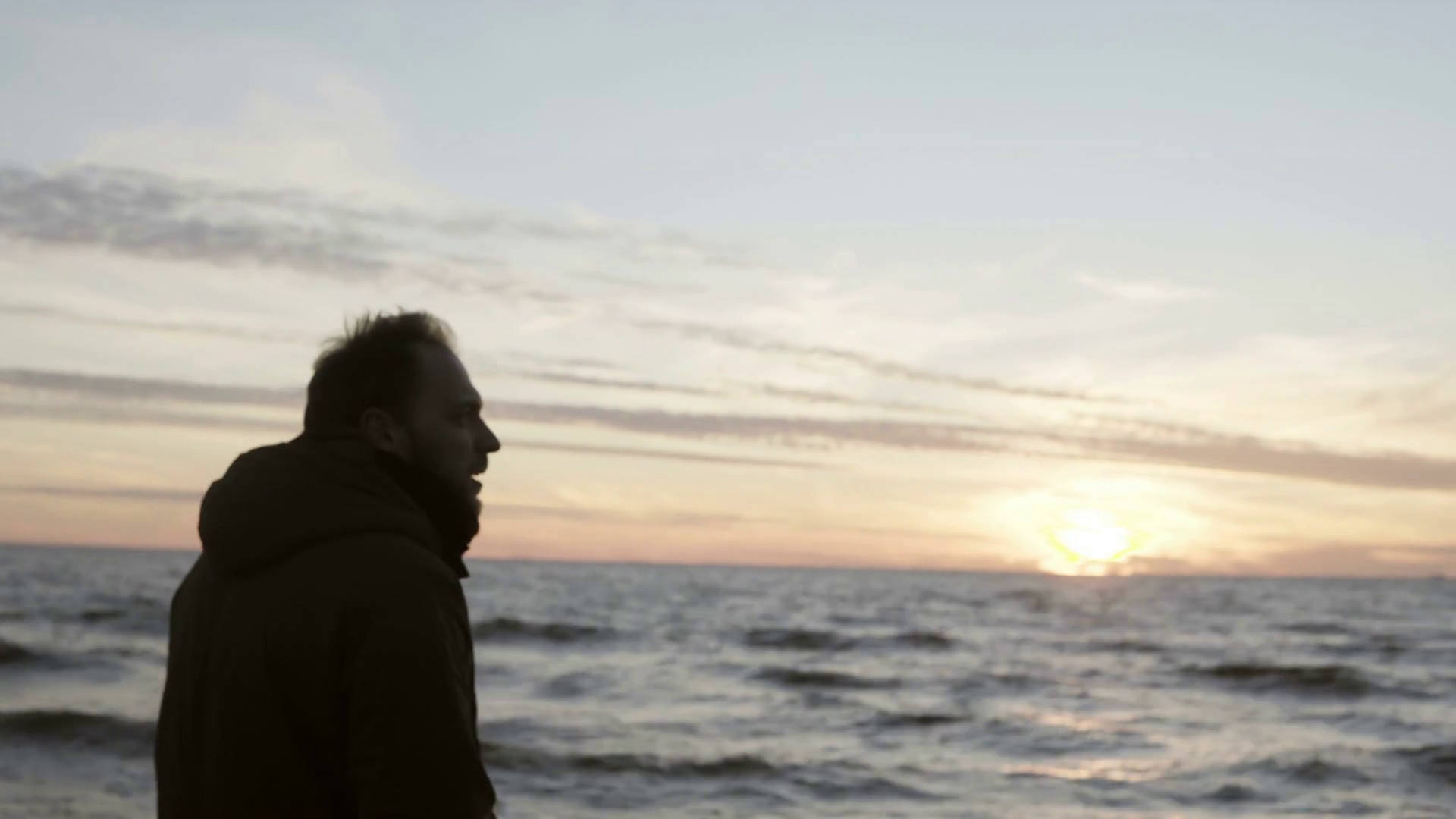 Young man walking in the shore of the sea alone and looking on the ...