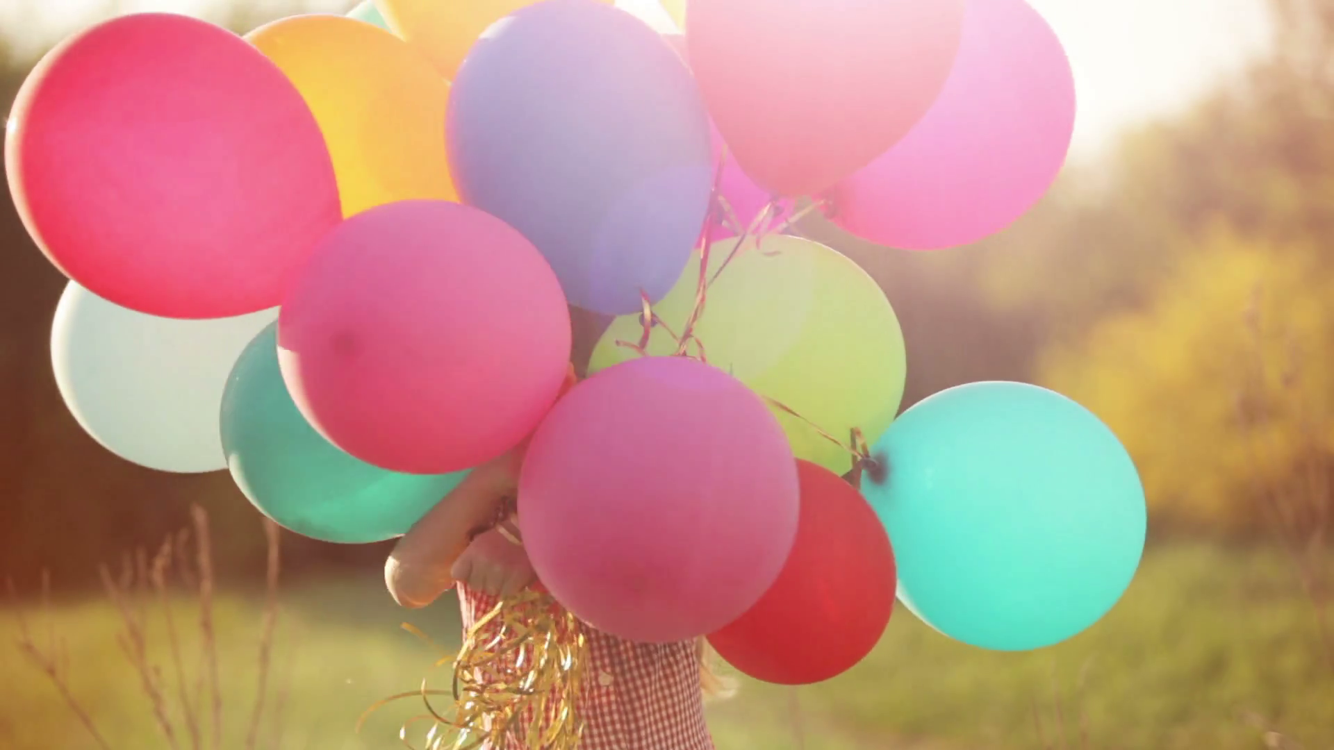 Girl spinning with balloons in the park and looking at camera. Lens ...