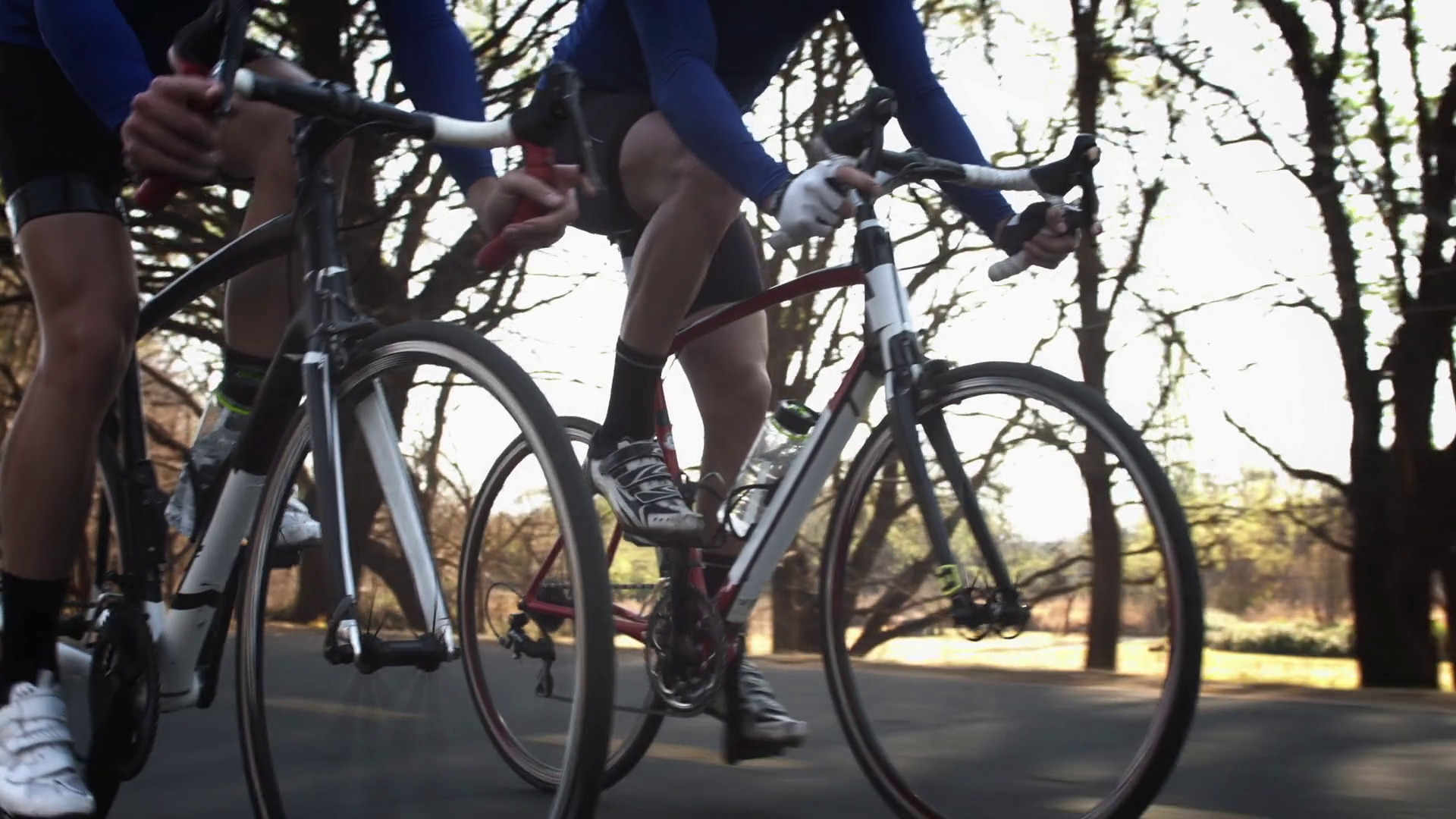 Steadicam close up shot of two healthy men peddling with cycling road ...