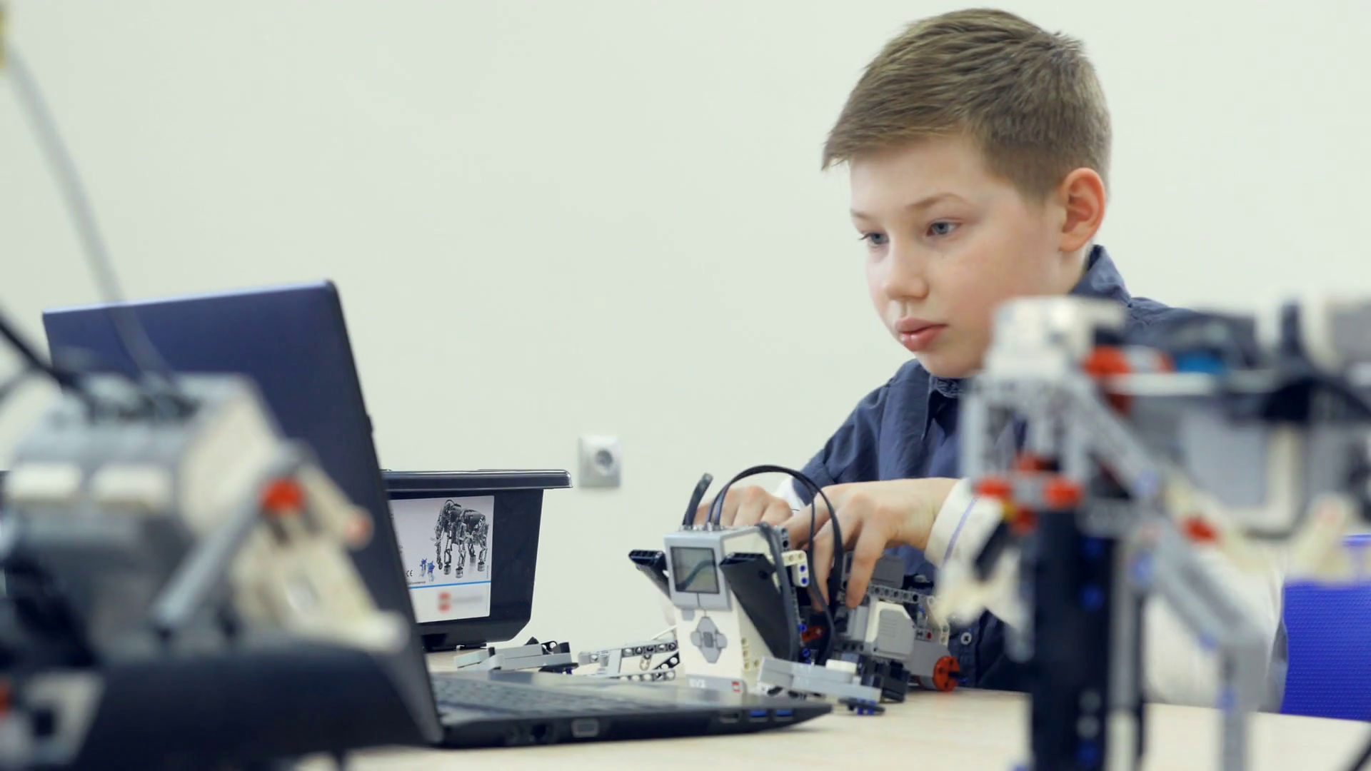 Student boy assembling robot in robotechnics school classroom. Engineer ...