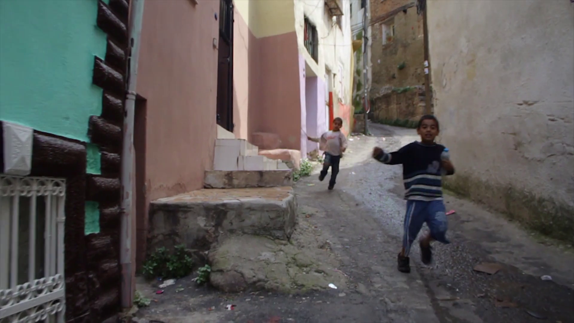 Turkey boys run into camera in slum, shacks at background. Colorful ...