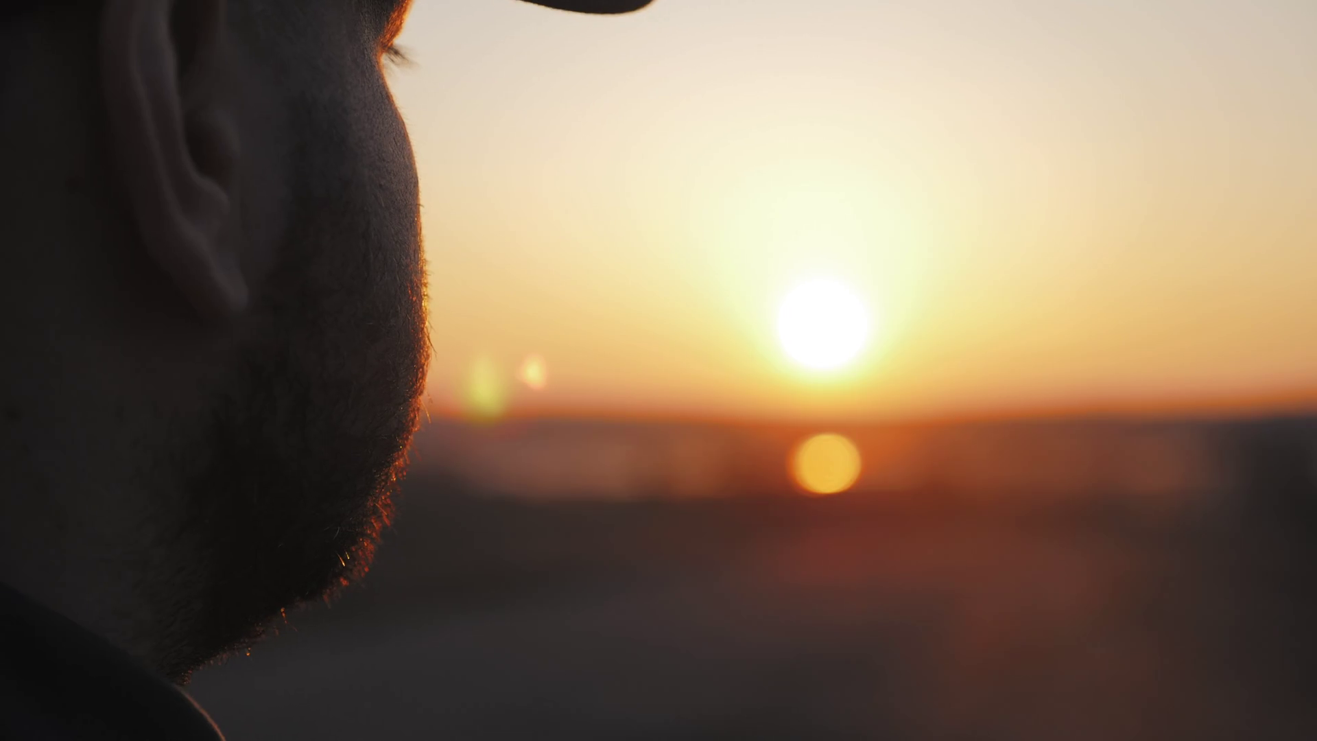A man with a beard looks into the distance at sunset. Close up of male ...