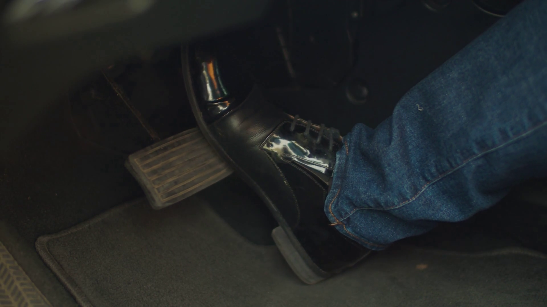 Close-up of male leg in trendy black leather shoe pressing brake pedal ...