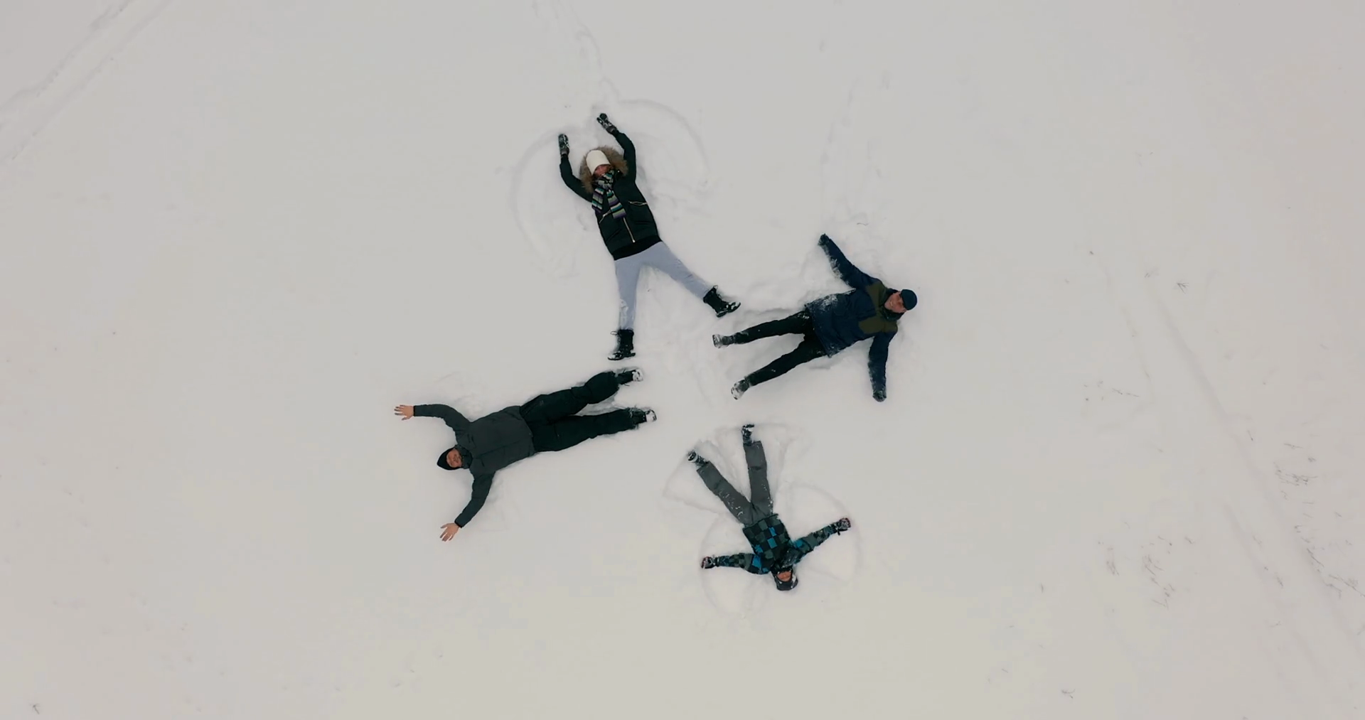 Aerial View A Group Of Young People Depict Snow Angels Lying On The Fresh Snow In The Form Of A