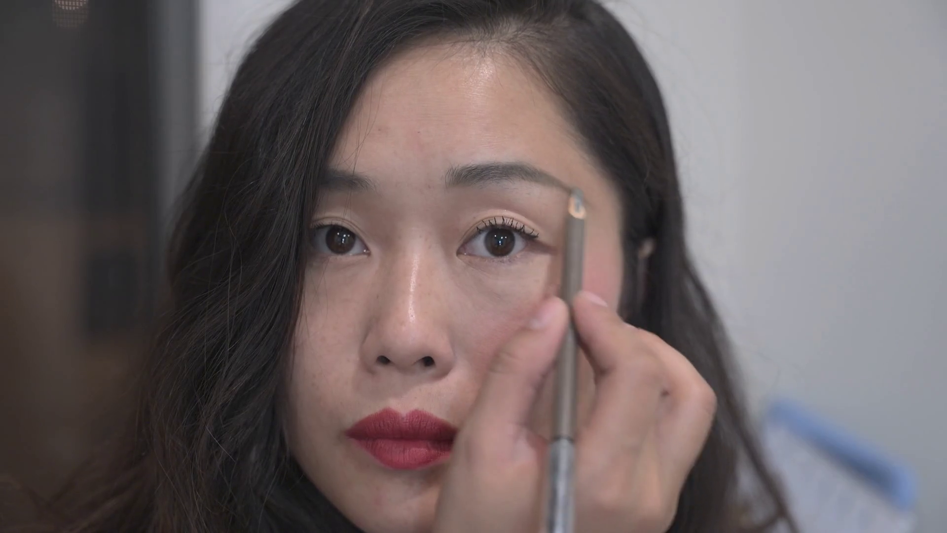 A young dark-haired Asian Chinese woman paints her eyebrows with an ...