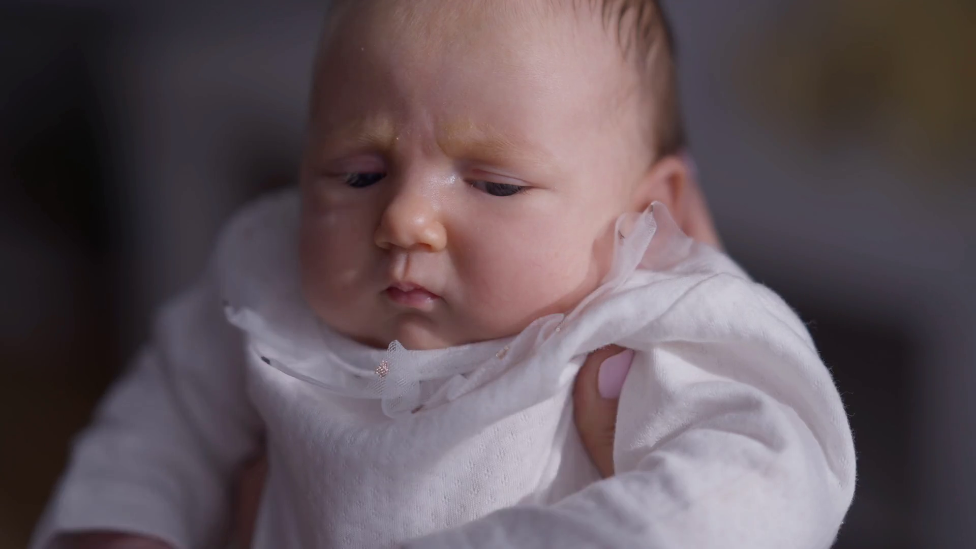 Headshot newborn baby girl with dissatisfied facial expression indoors ...