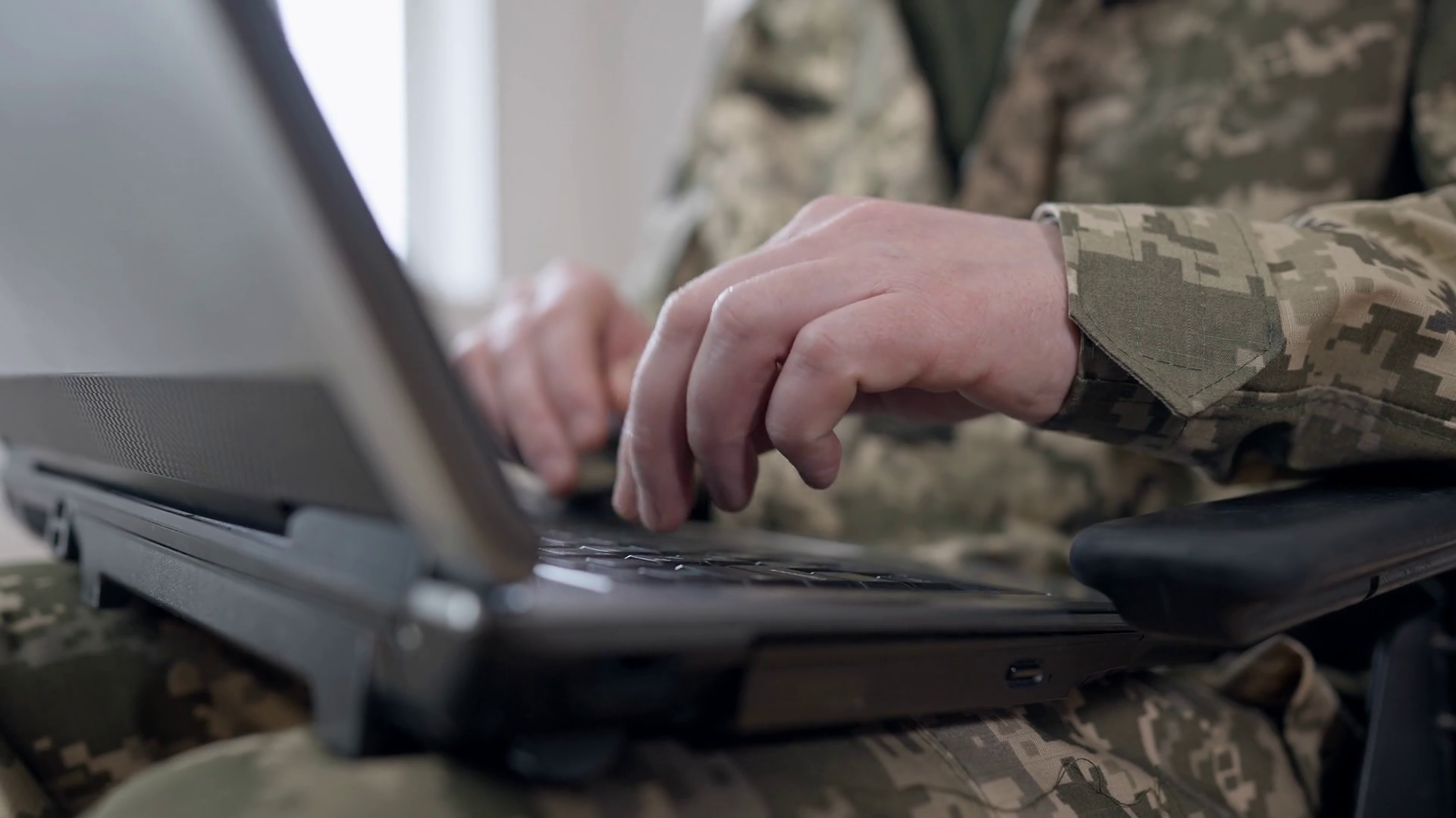 Close-up of male hands of military man typing on laptop keyboard ...