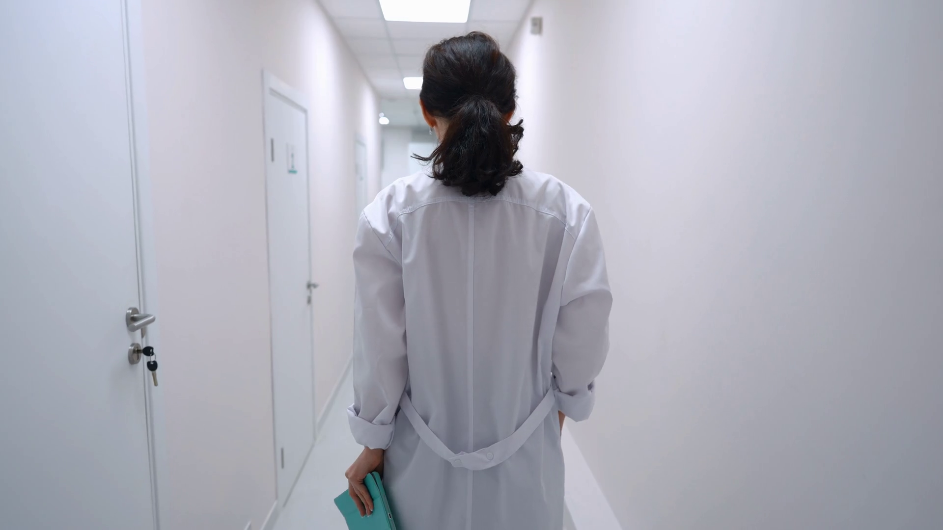 Back view professional confident doctor walking along hospital corridor ...