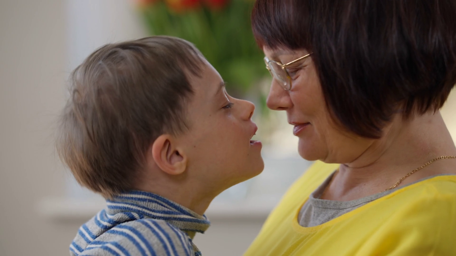 Close-up positive mother kissing autistic son smiling talking. Side ...