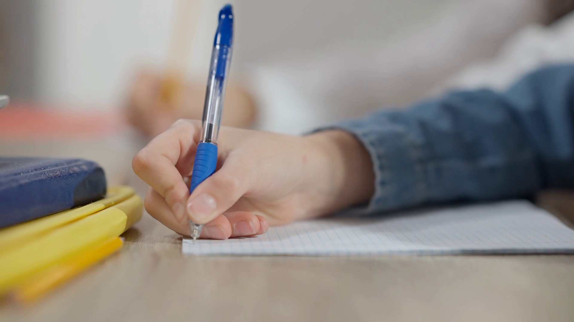 Close-up hand of Caucasian schoolgirl writing in workbook in school ...