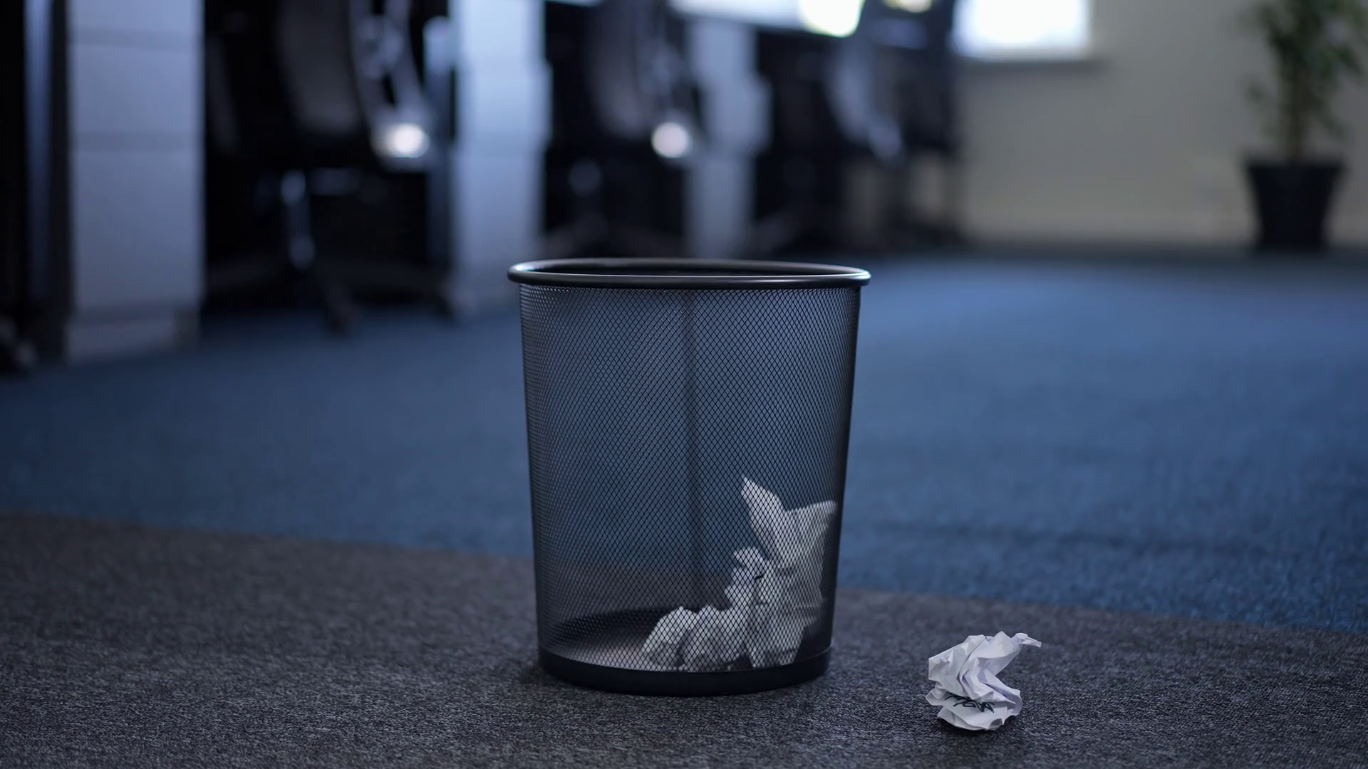 Close-up office trash bin with crumpled paper ball falling aside ...