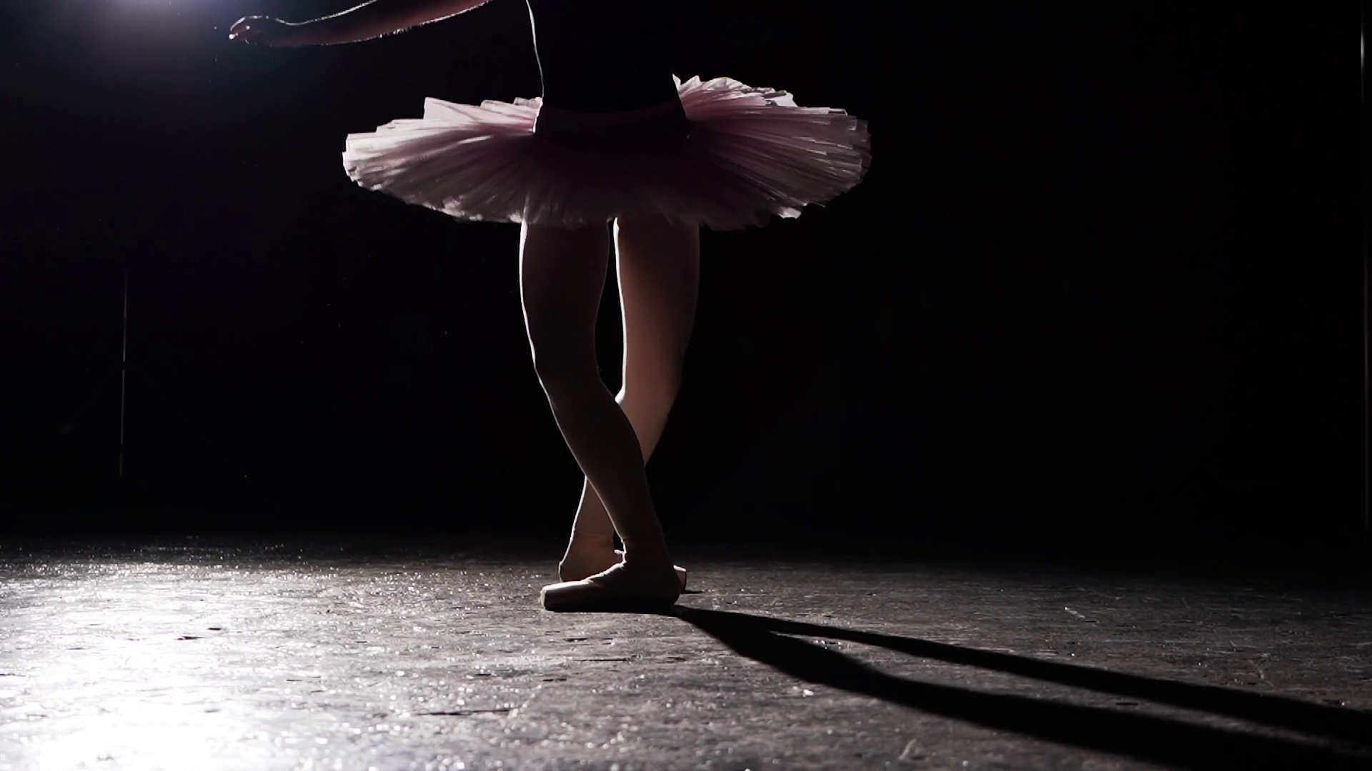 Ballerina performing pirouettes on black background in studio. Female ...