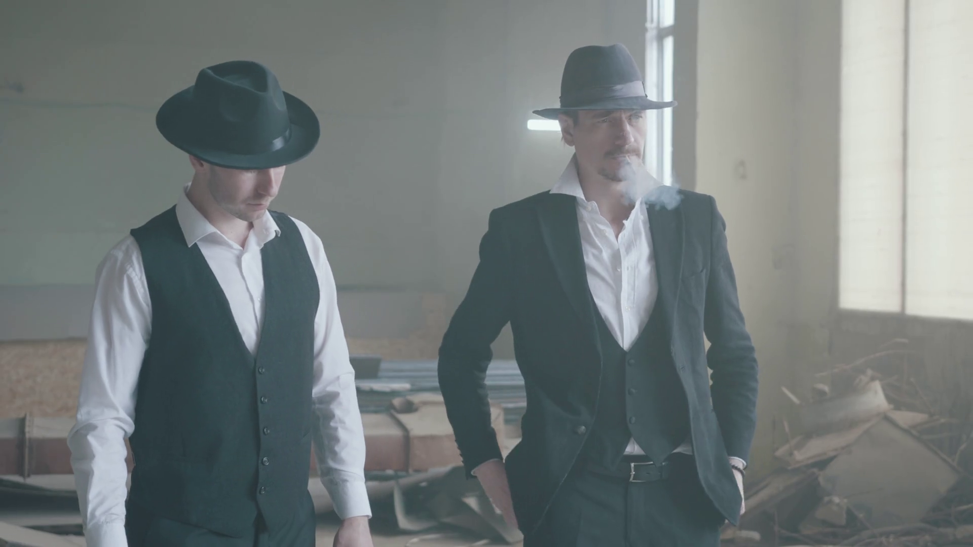 Portrait of two smoking gangsters walking in the old dilapidated ...