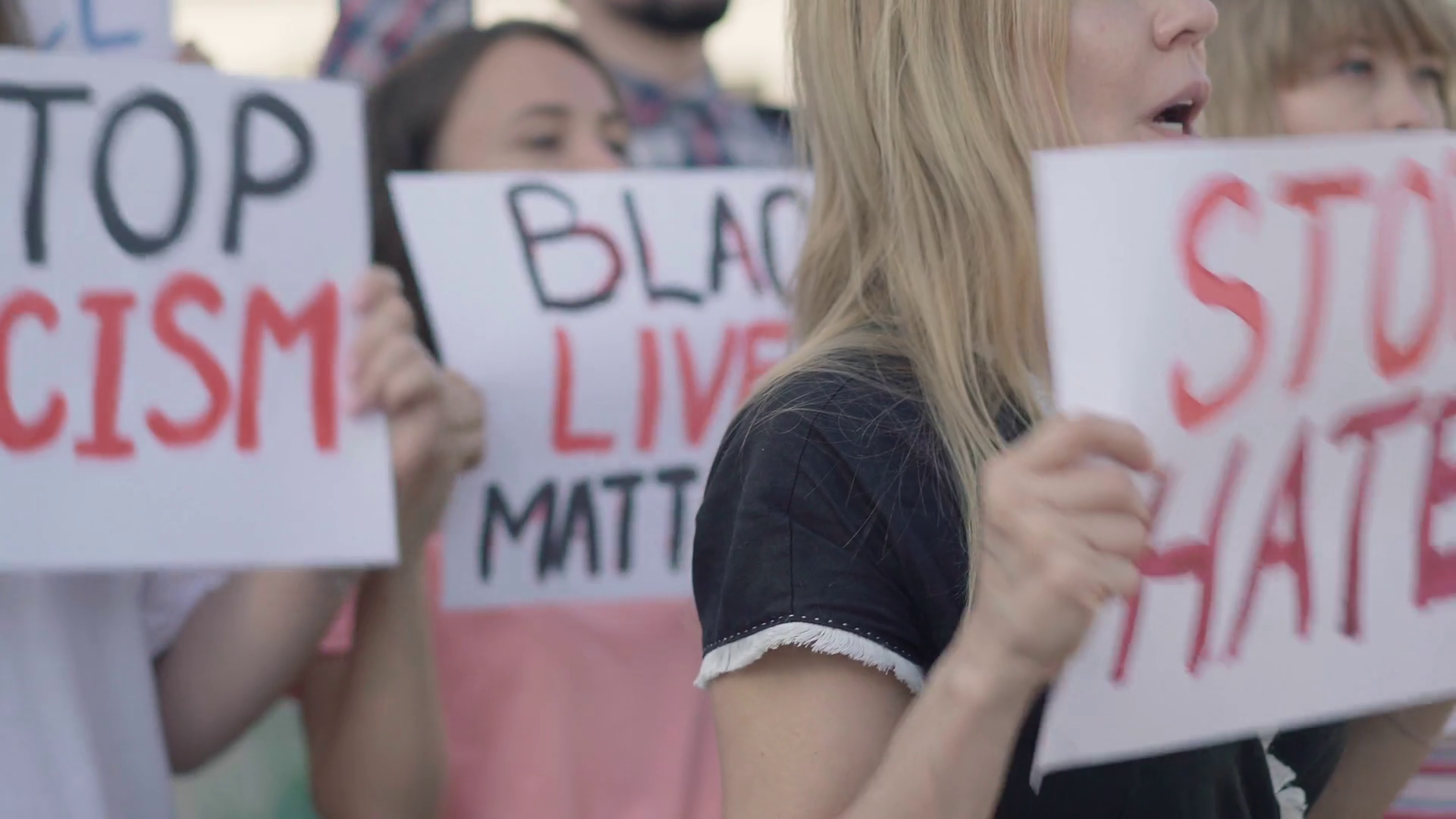 Side view of activists crowd with anti-racism banners shouting. Group ...