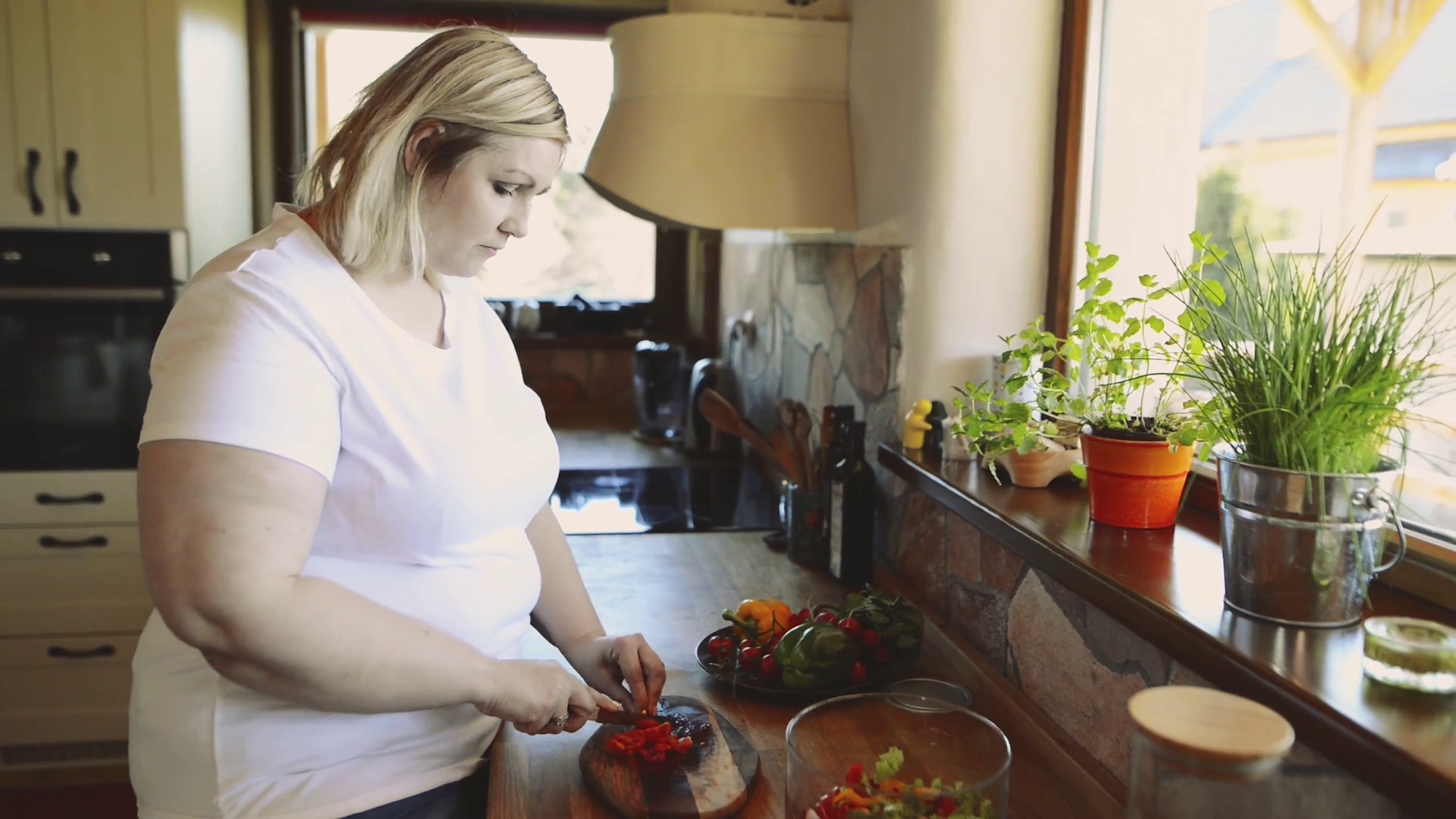 Overweight woman at home preparing vegetable salad in the kitchen ...