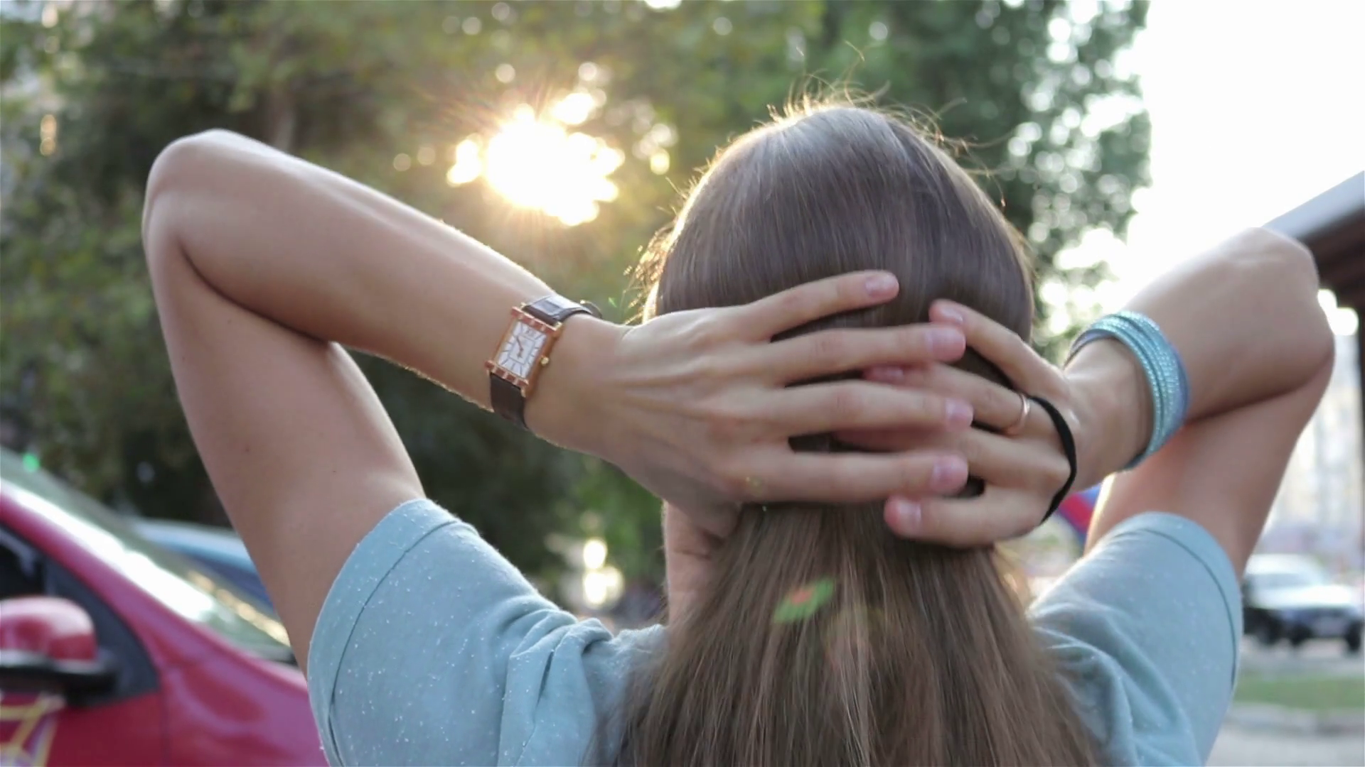 Young woman tying hair on the street in the summer, back view, slow ...